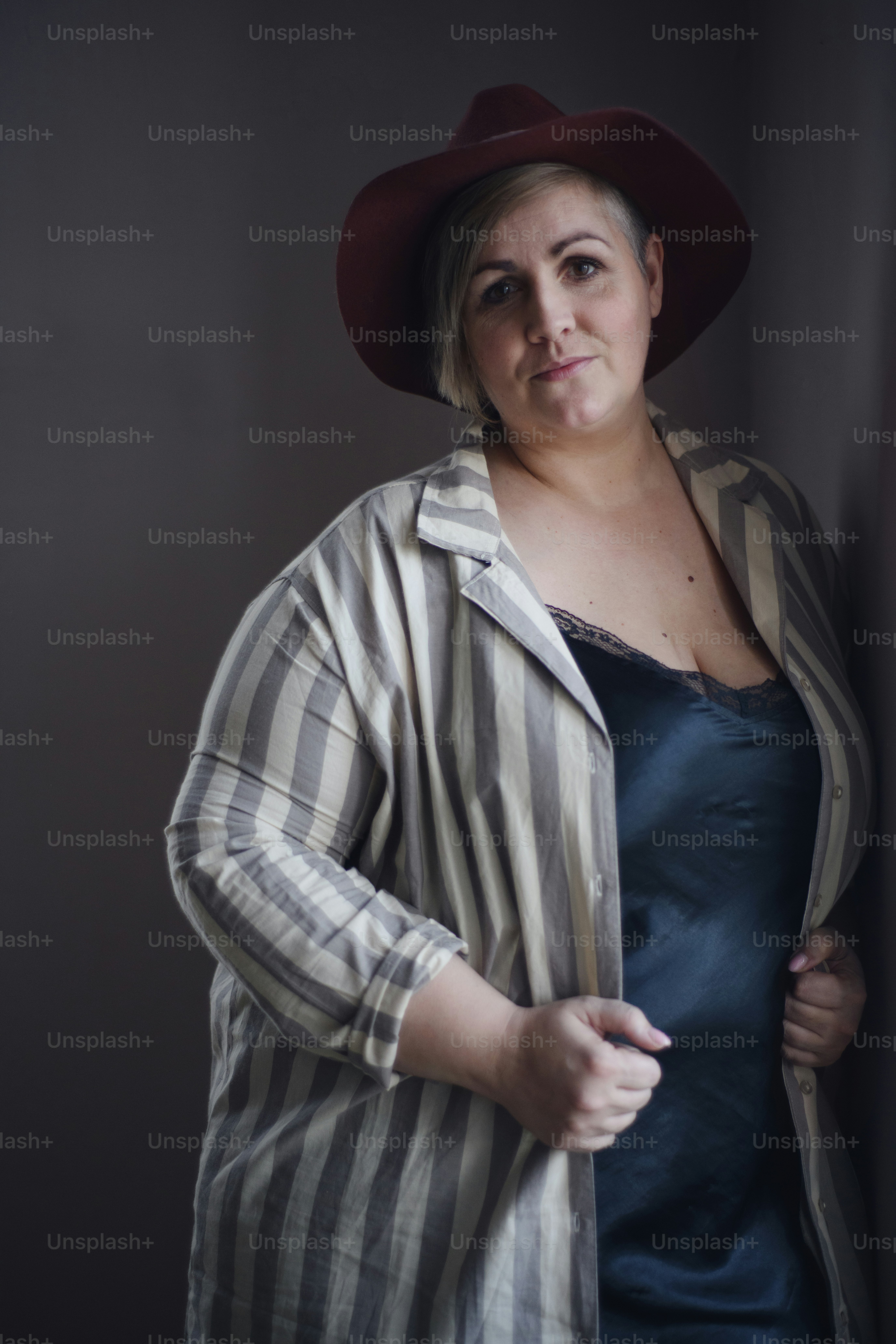 A lonely fat woman standing and looking through the window at home ...