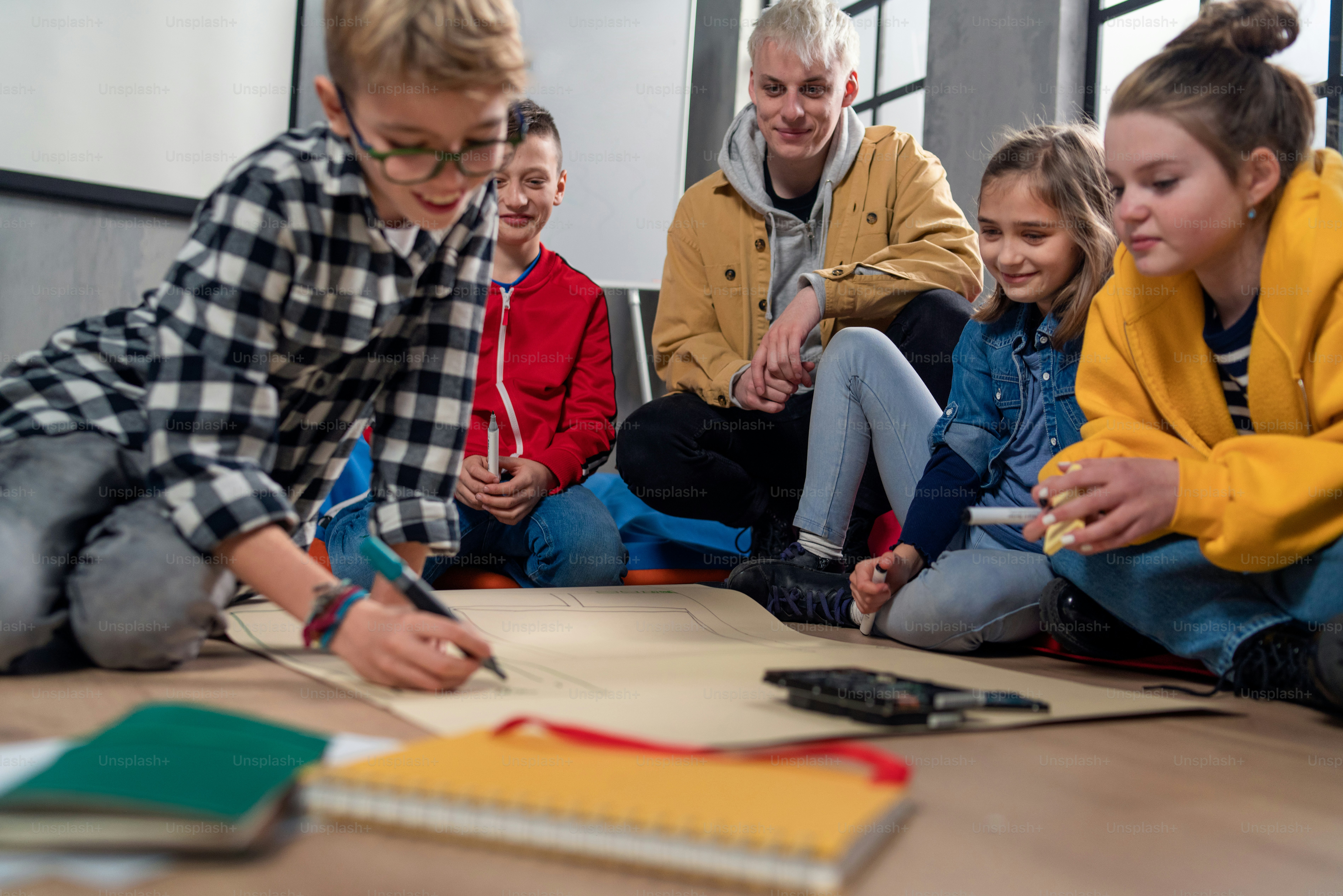 A group of happy kids with their teacher working on project together at ...