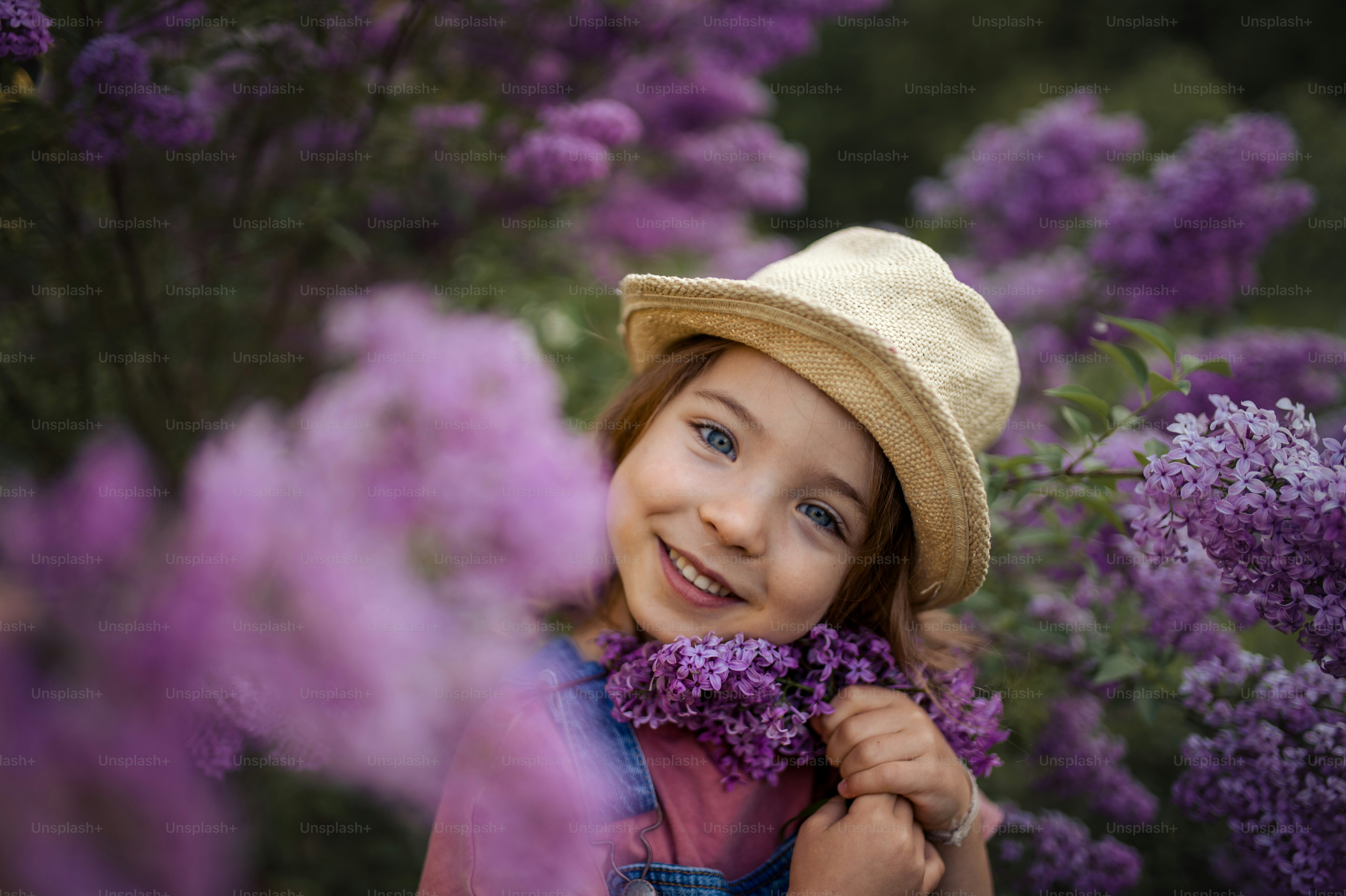 A portrait of a cheerful little girl in nature blooming lilac-purple ...
