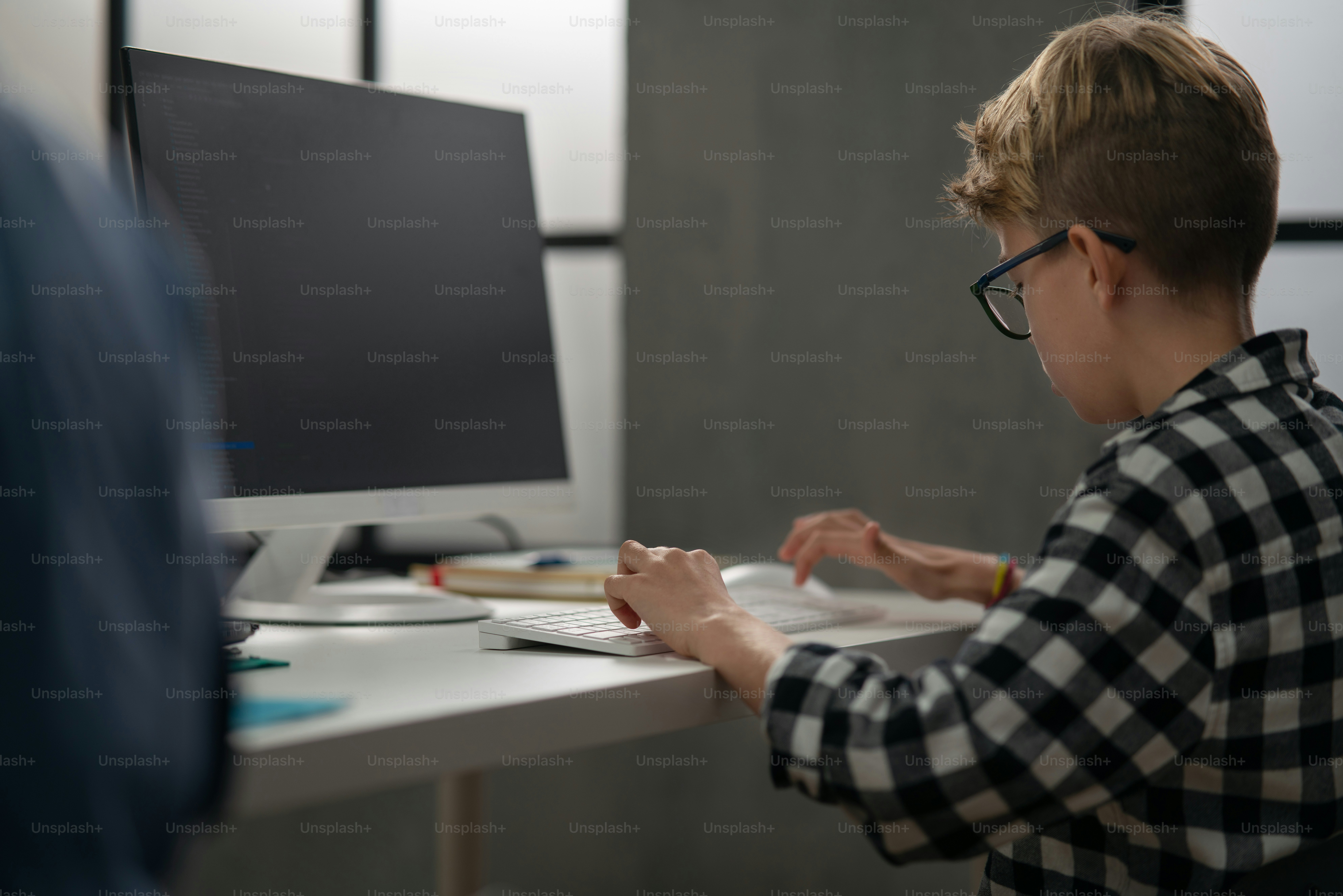 A rear view ofschoolboy using computer in classroom at school photo ...