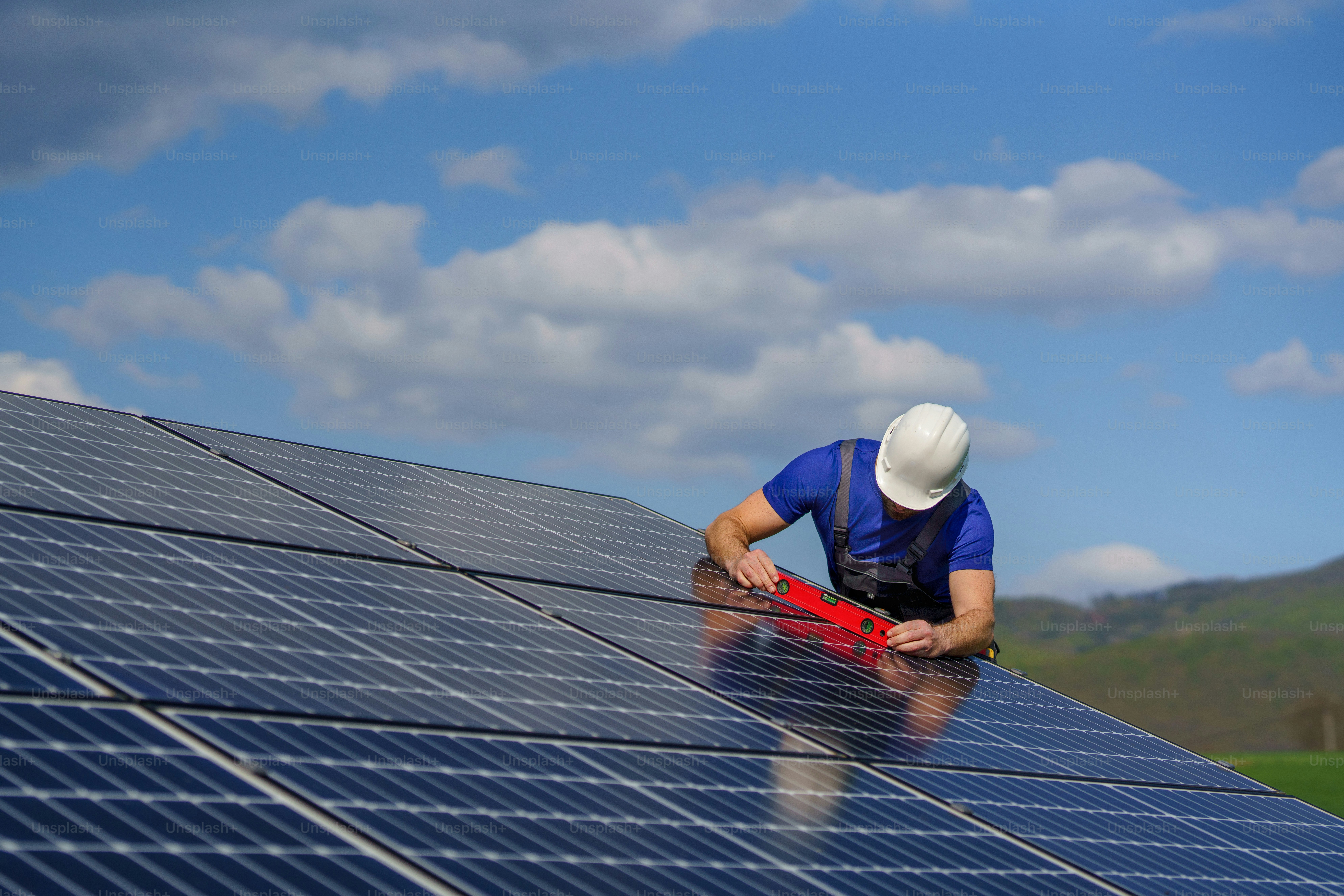 A man worker installing solar photovoltaic panels on roof, alternative ...