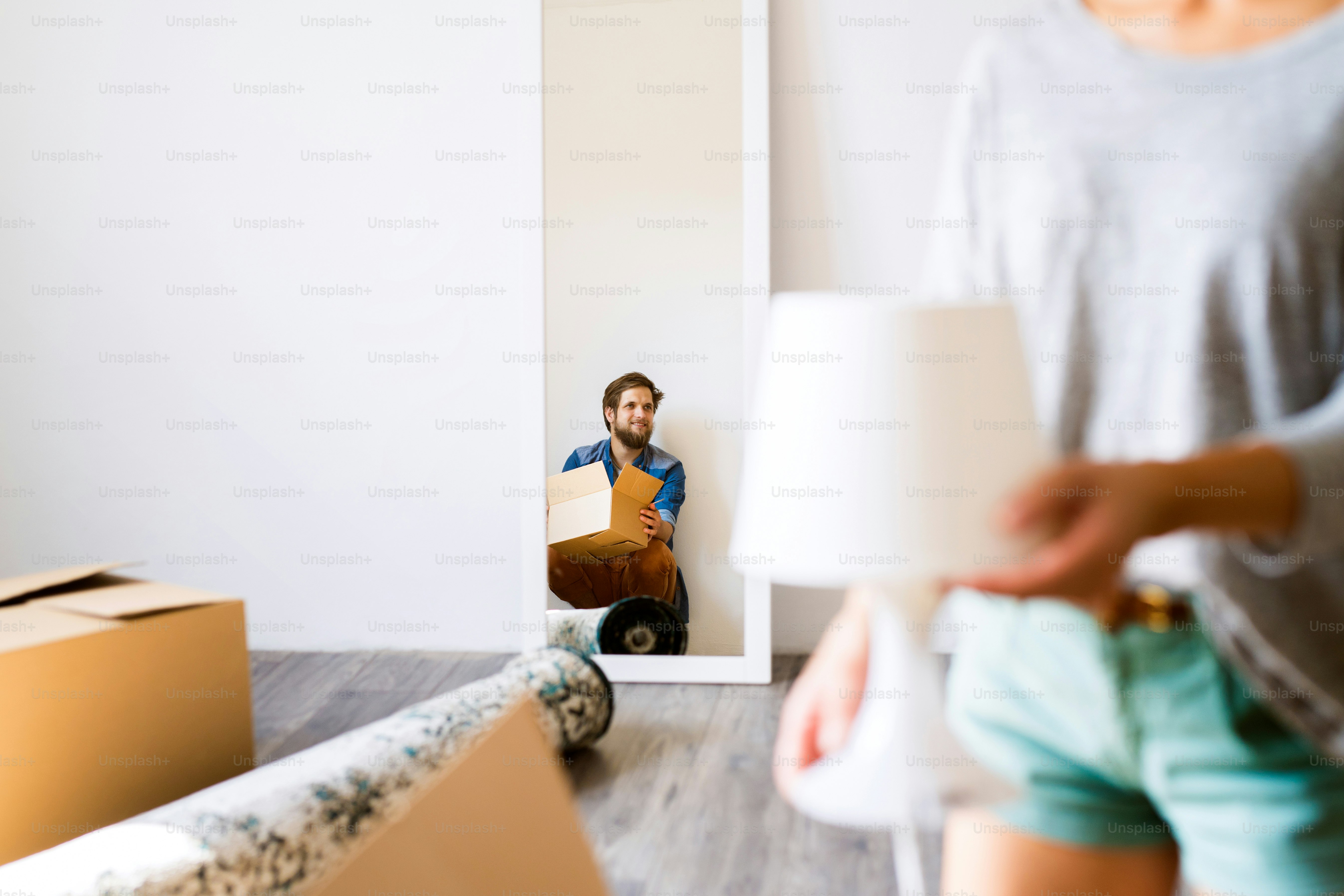 Young married couple moving in new house, cardboard boxes surrounding ...