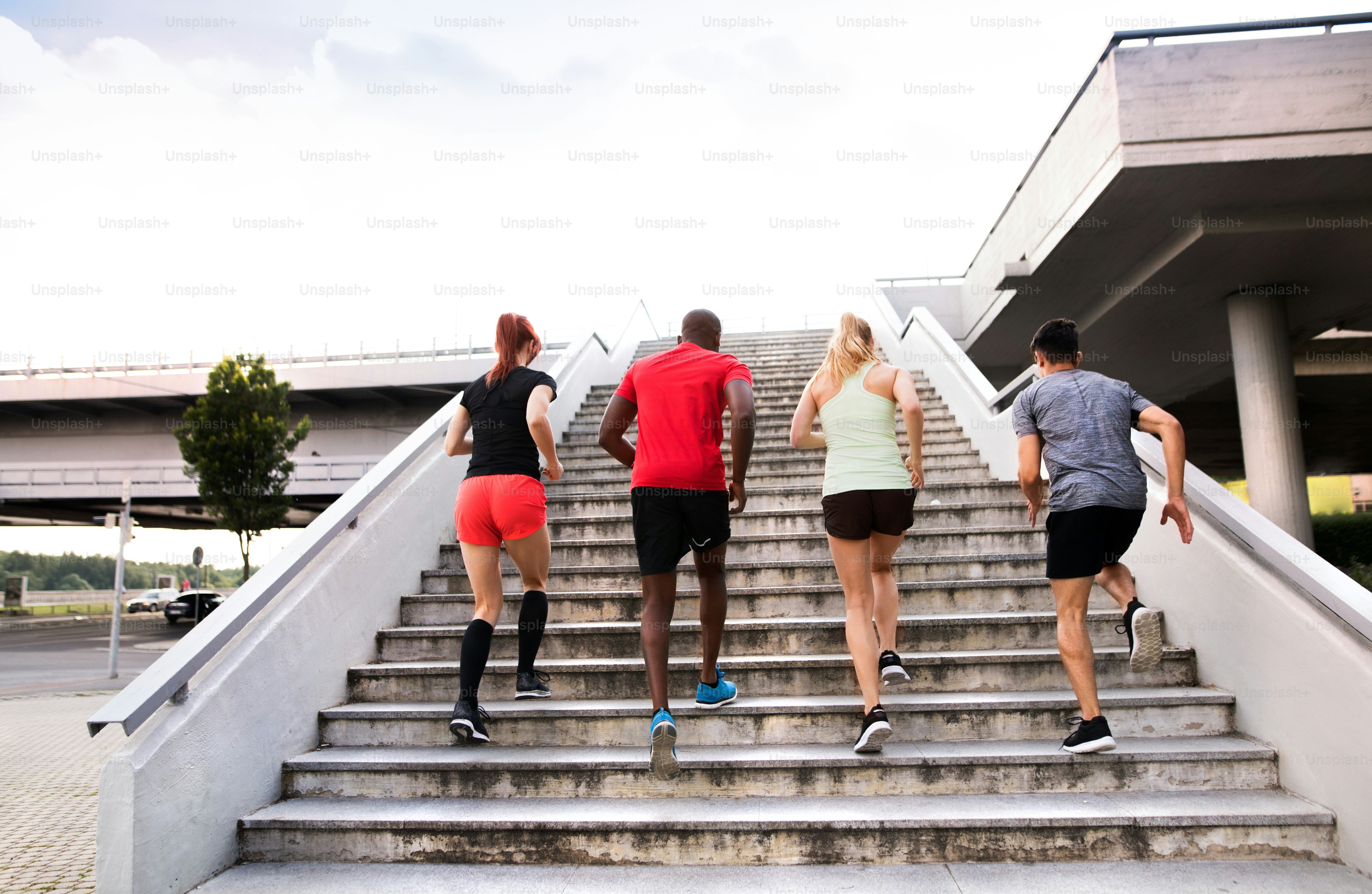 Beautiful young people in the city running together up the stairs, rear ...