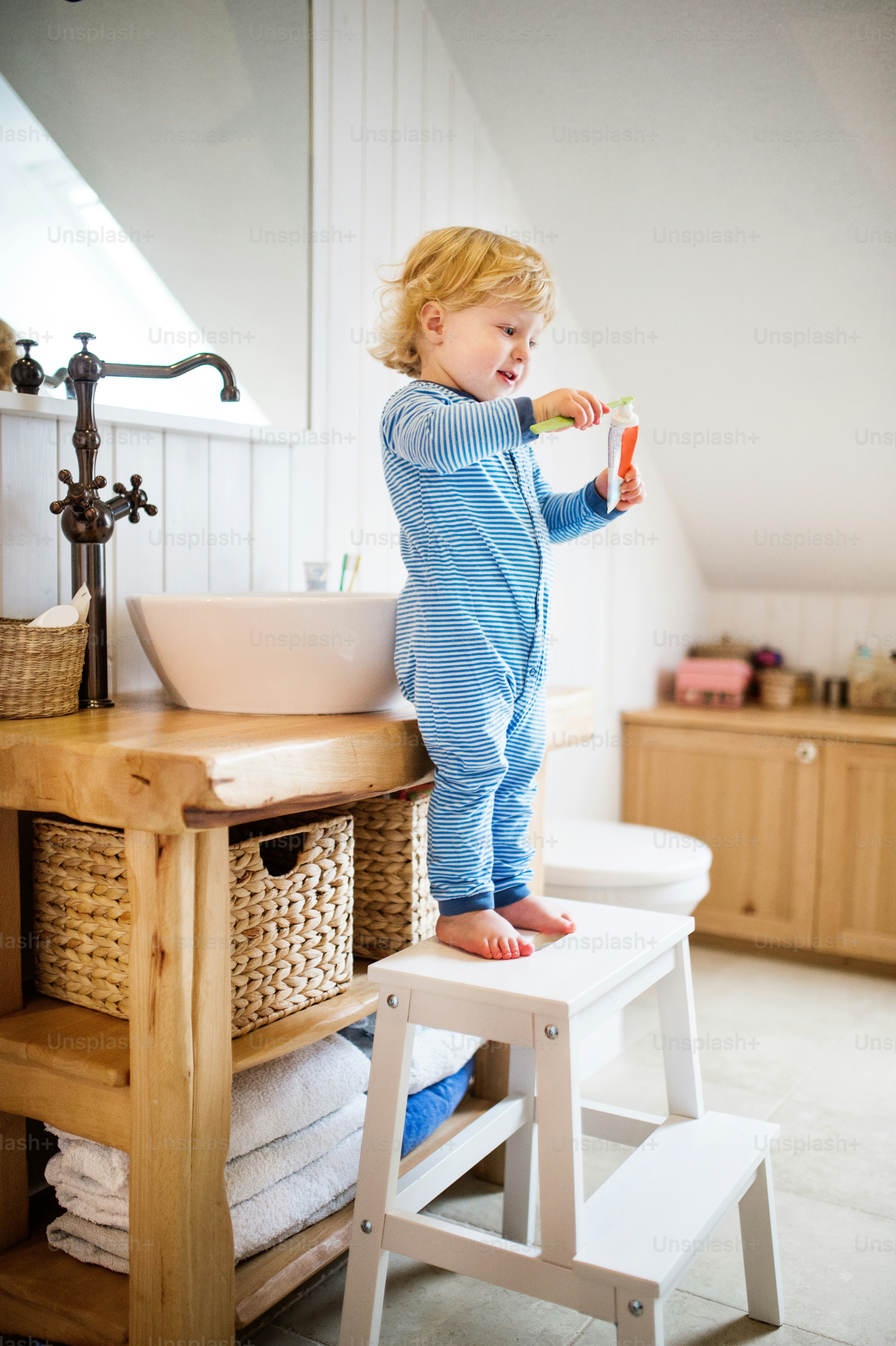 Cute toddler brushing his teeth in the bathroom. Little boy standing on ...