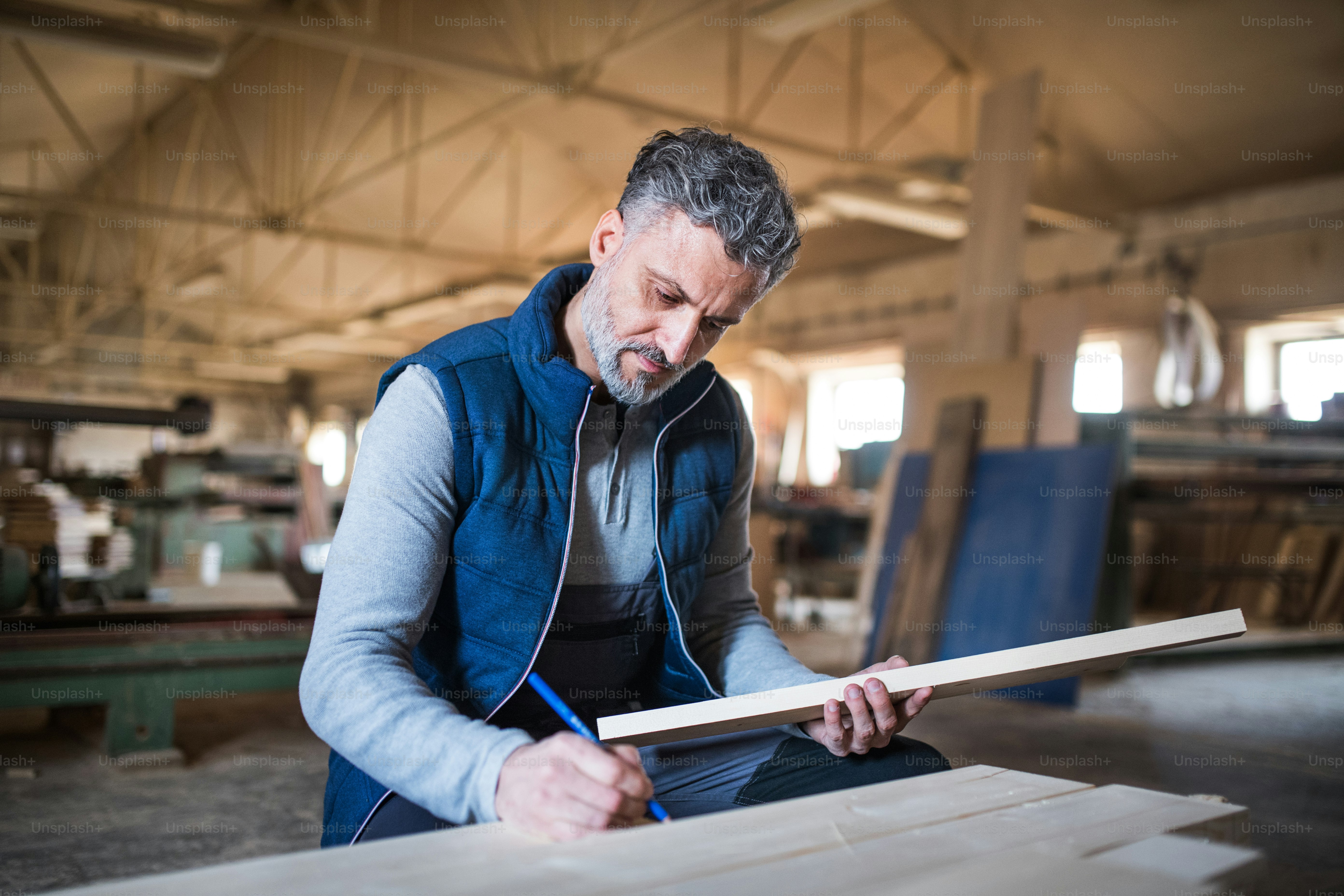 A mature man worker in the carpentry workshop, working with wood. photo ...