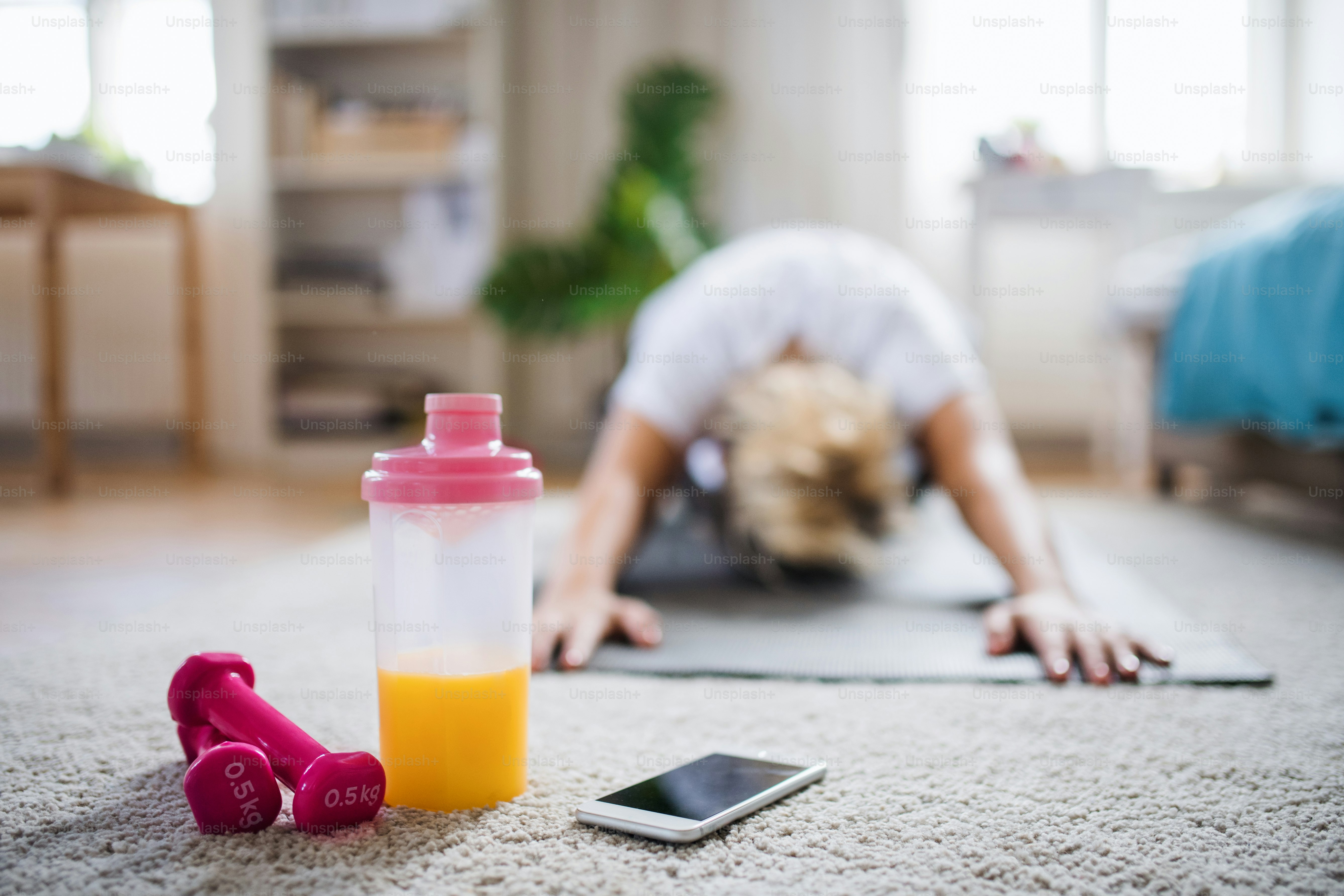 A young woman doing exercise on the floor indoors at home, front view ...