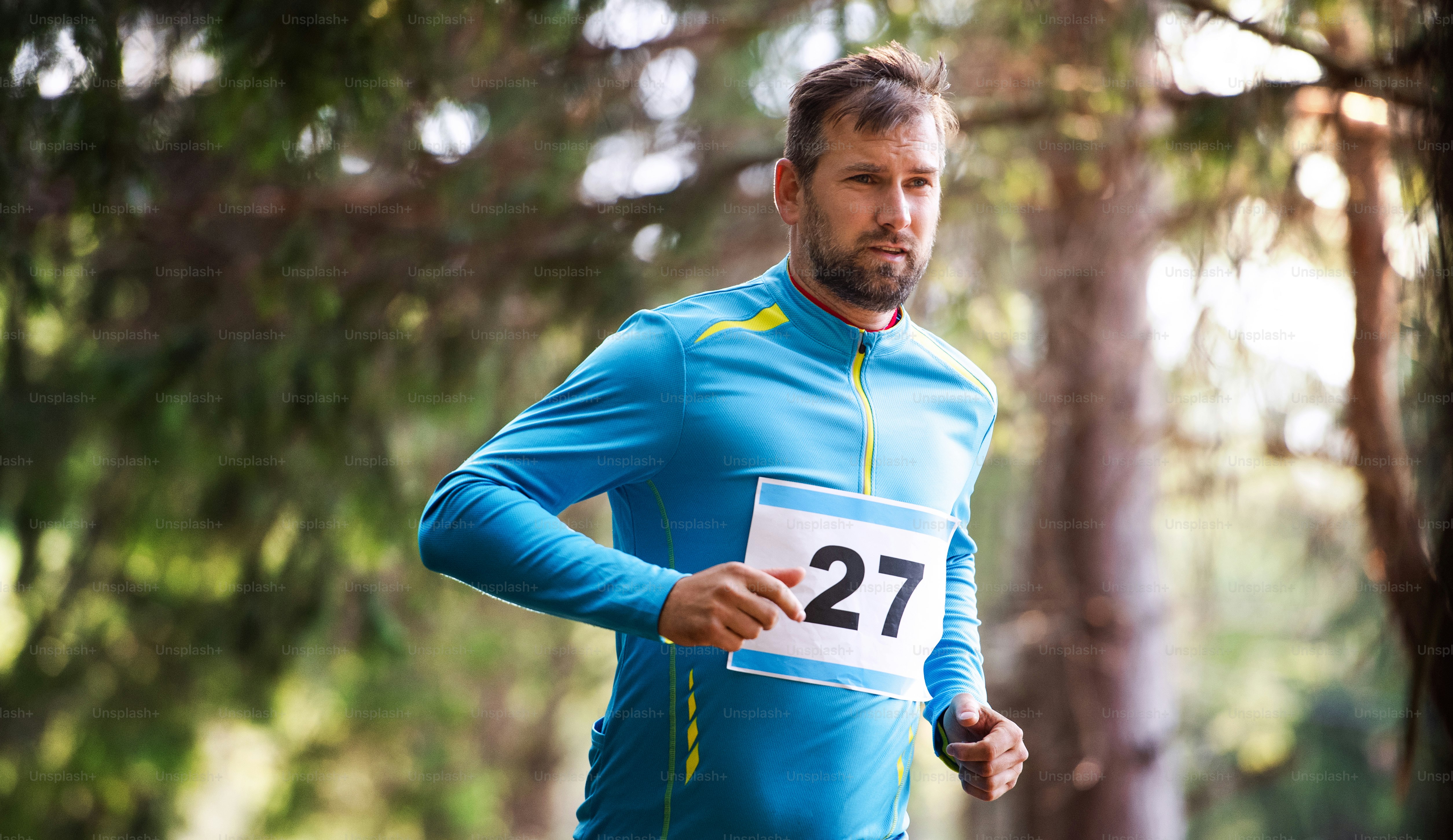 A front view of young man running a race competition in nature. Copy ...