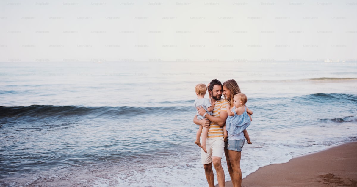 Une Jeune Famille Avec Deux Enfants En Bas âge Debout Sur La Plage