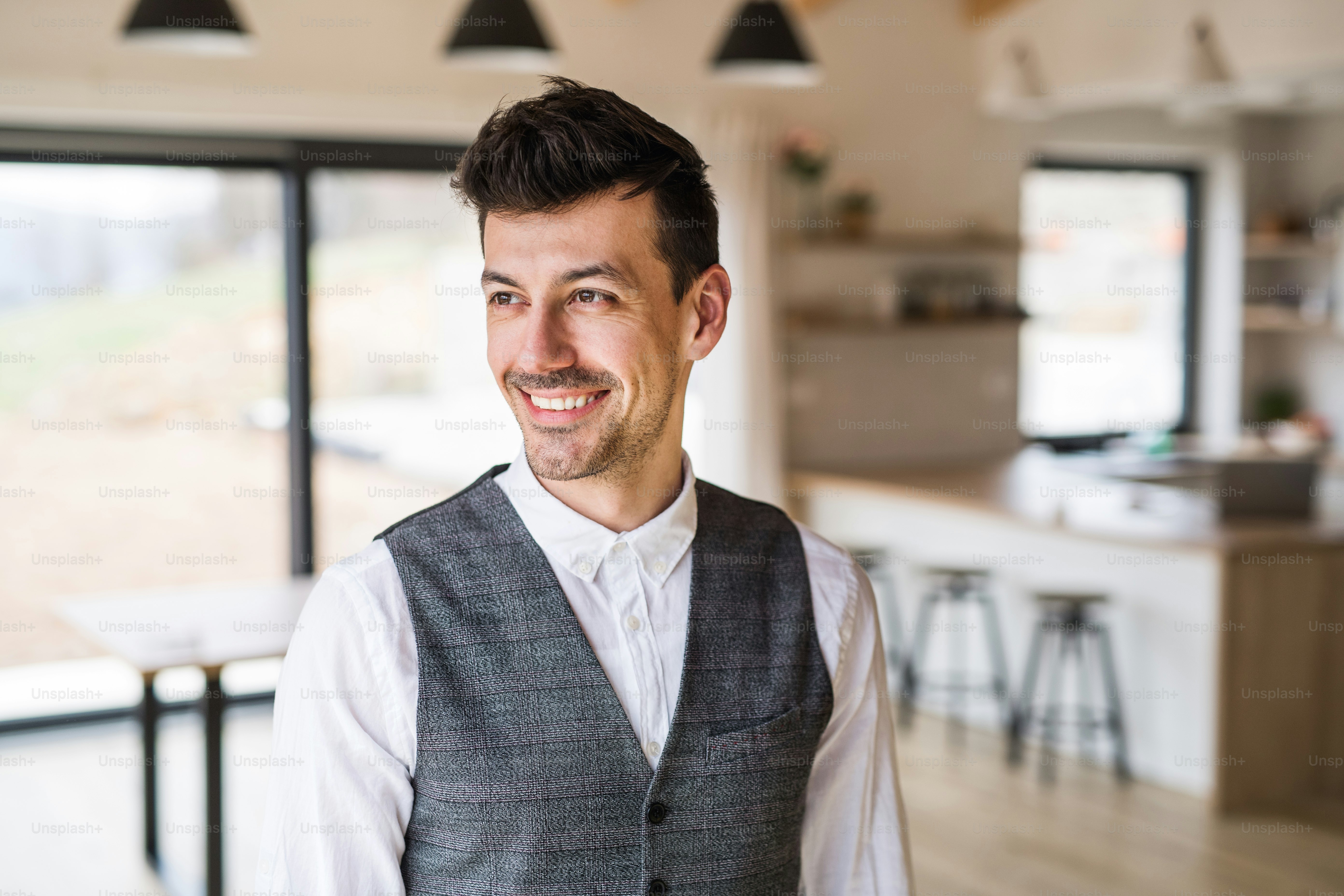 Front view portrait of young man standing indoors at home, laughing ...