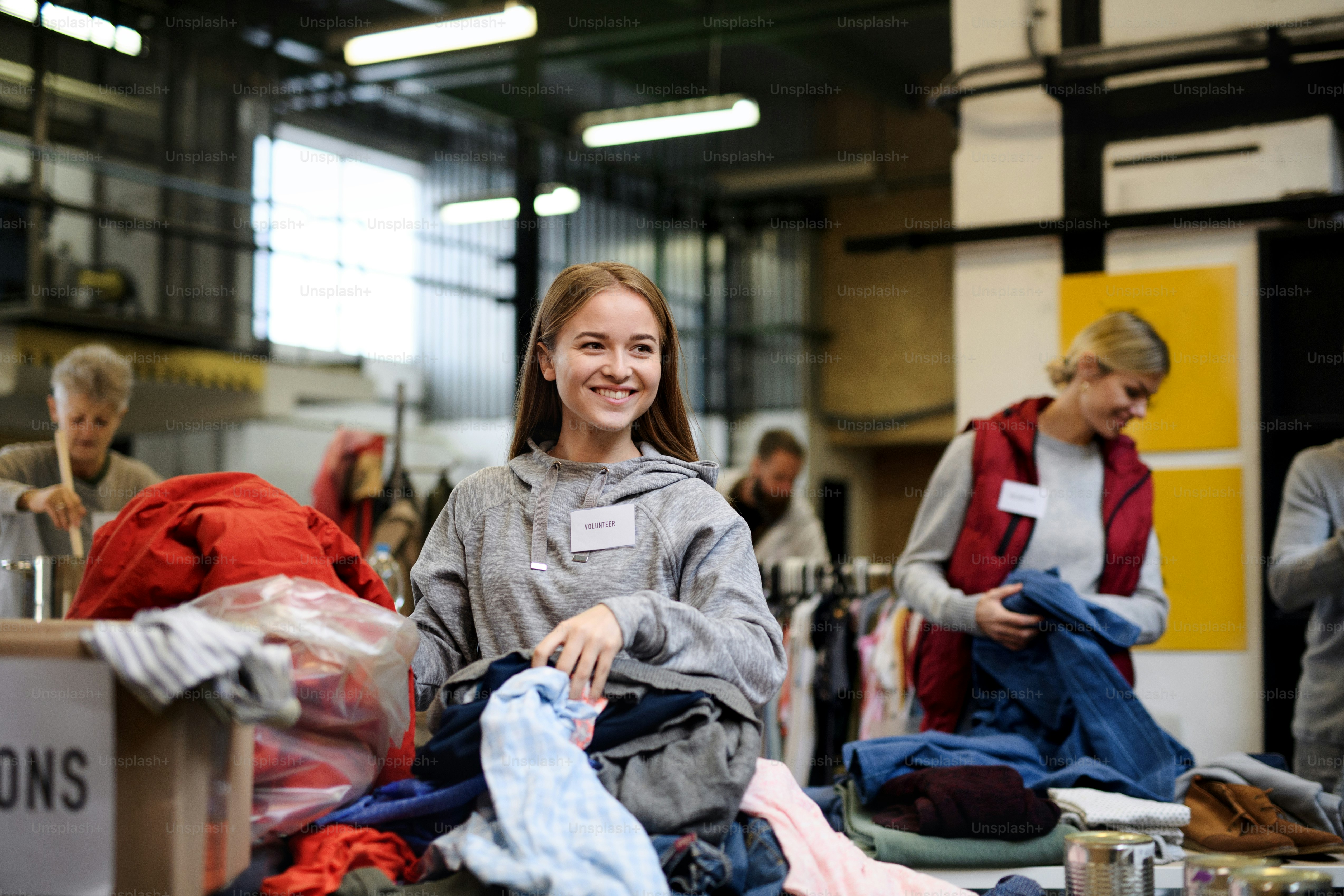 Portrait of volunteers sorting out donated clothes in community charity ...