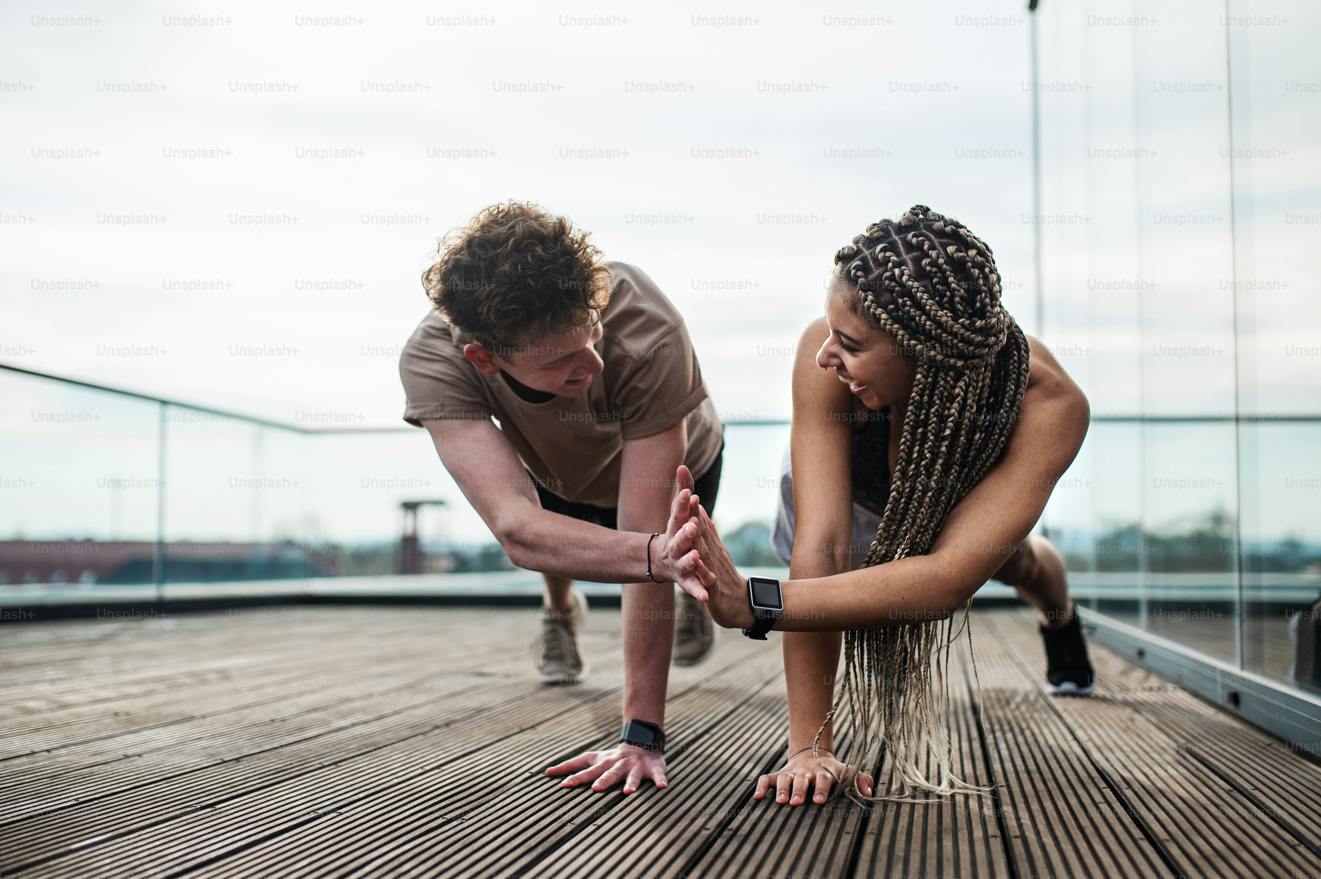 Happy young couple doing exercise outdoors on terrace, sport and ...