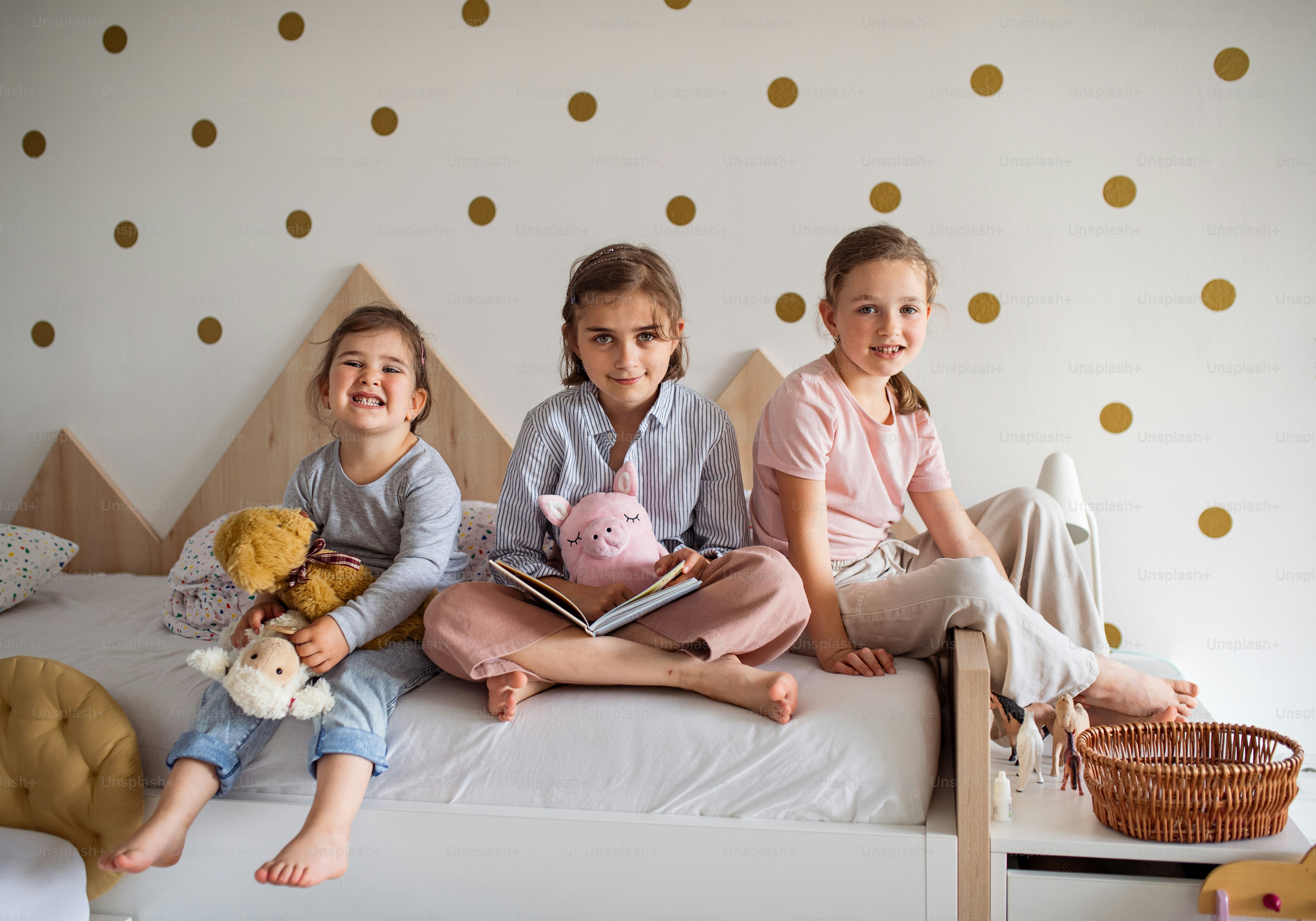 A portrait of three girls sisters indoors at home, looking at camera ...