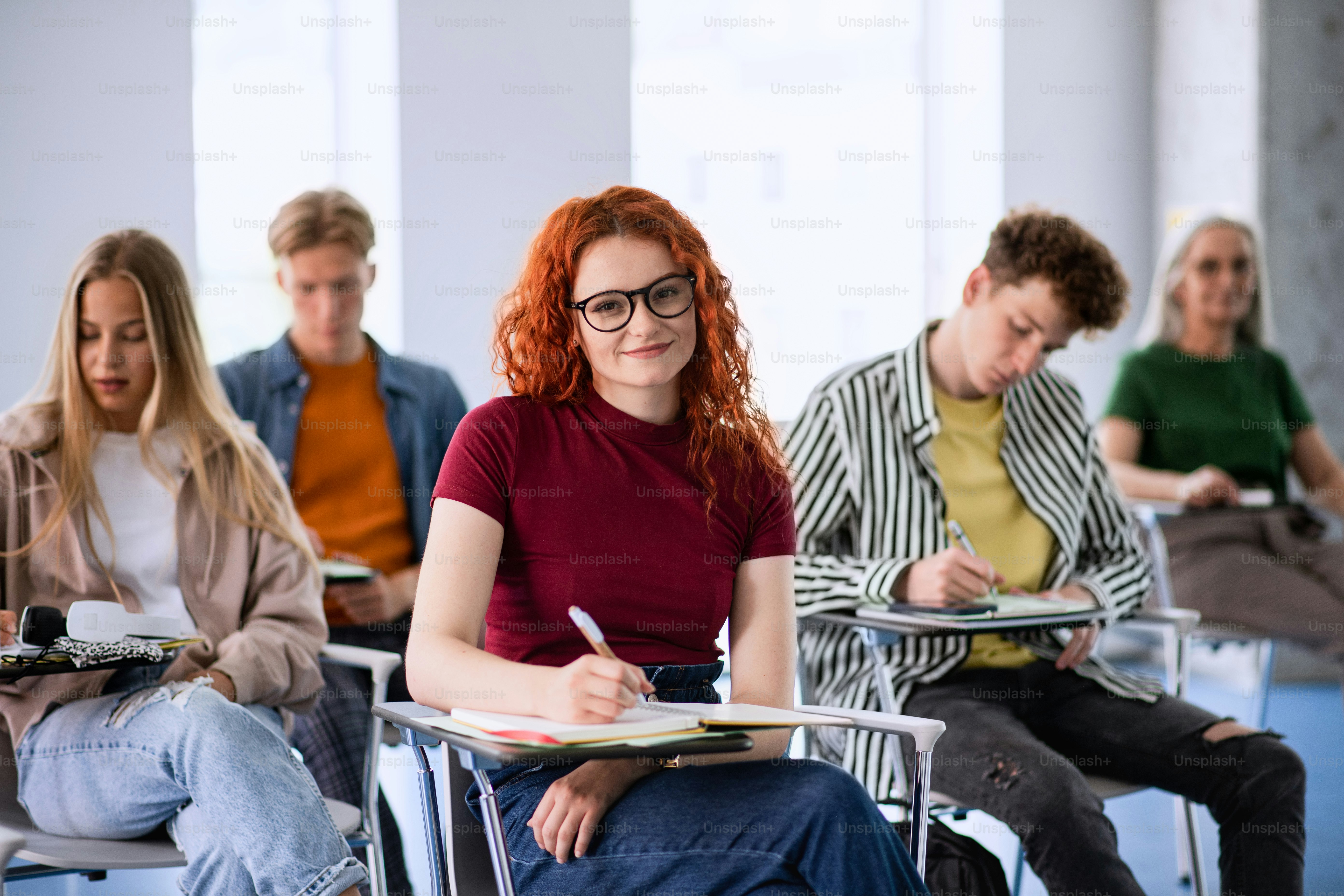 A portrait of group of university students sitting in classroom indoors ...