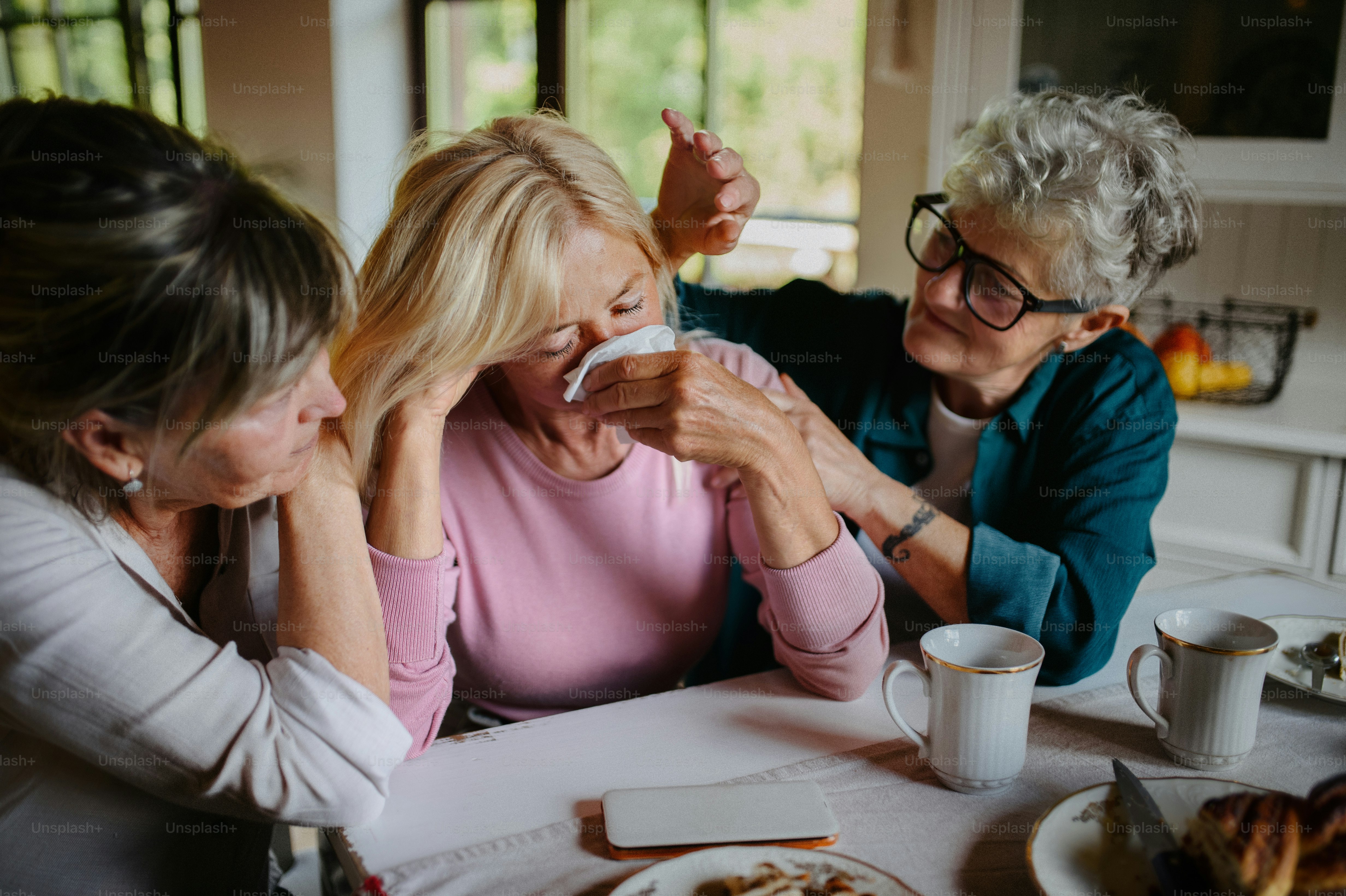 Female senior friends consloing a sad friend indoors at home. photo ...