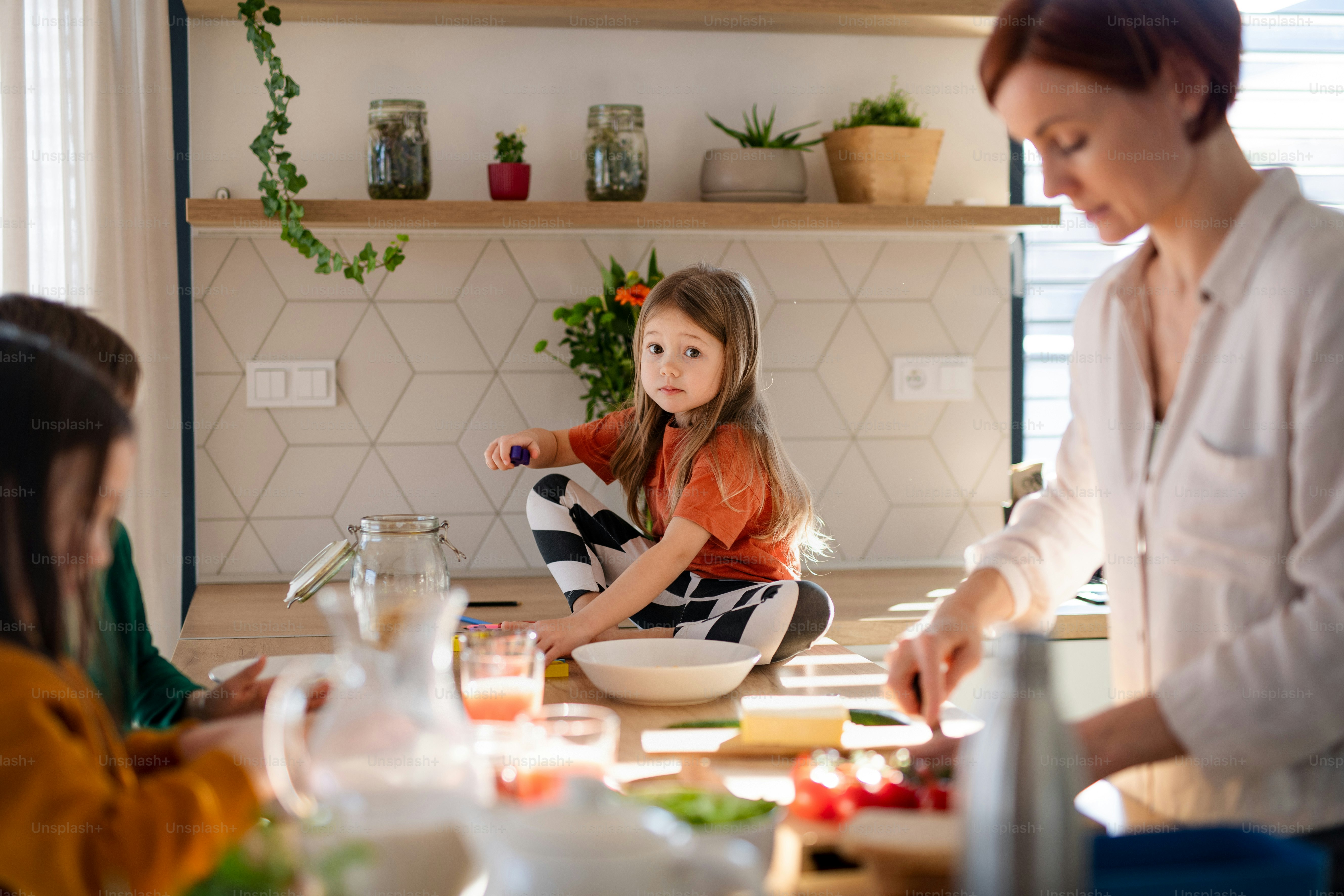 A mother of three little children preparing breakfast in kitchen at ...