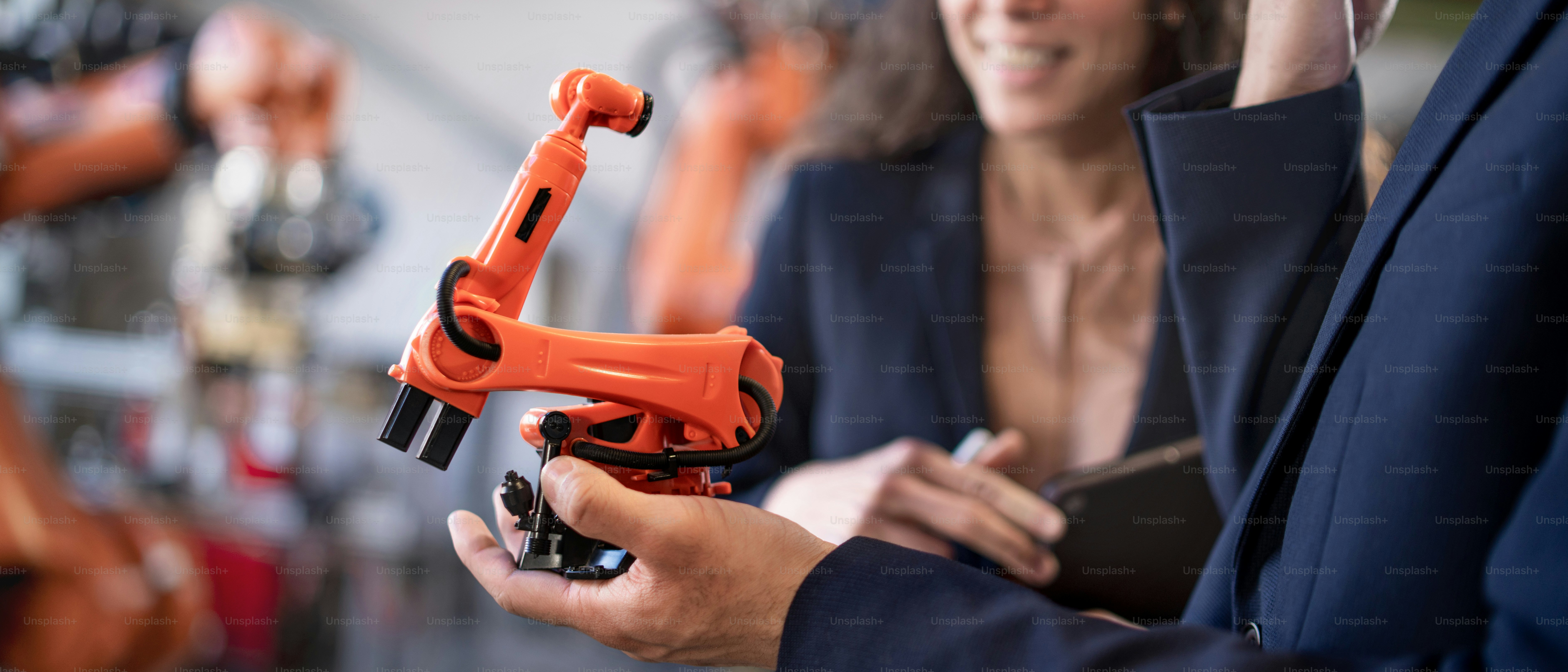 A close-up of man engineer holding model of industrial robotic arm and ...