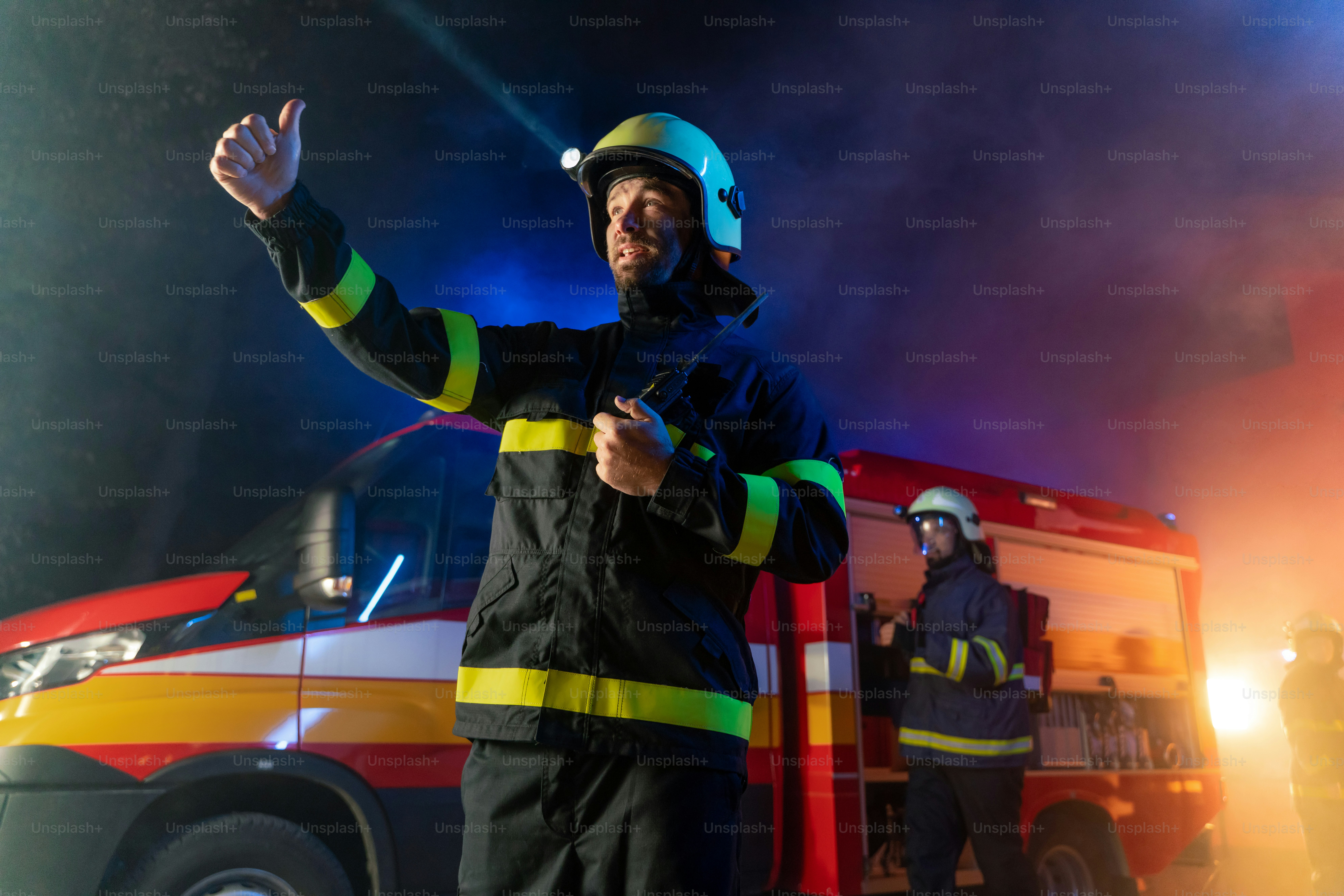 A low angle view of m firefighter talking to walkie talkie with fire ...