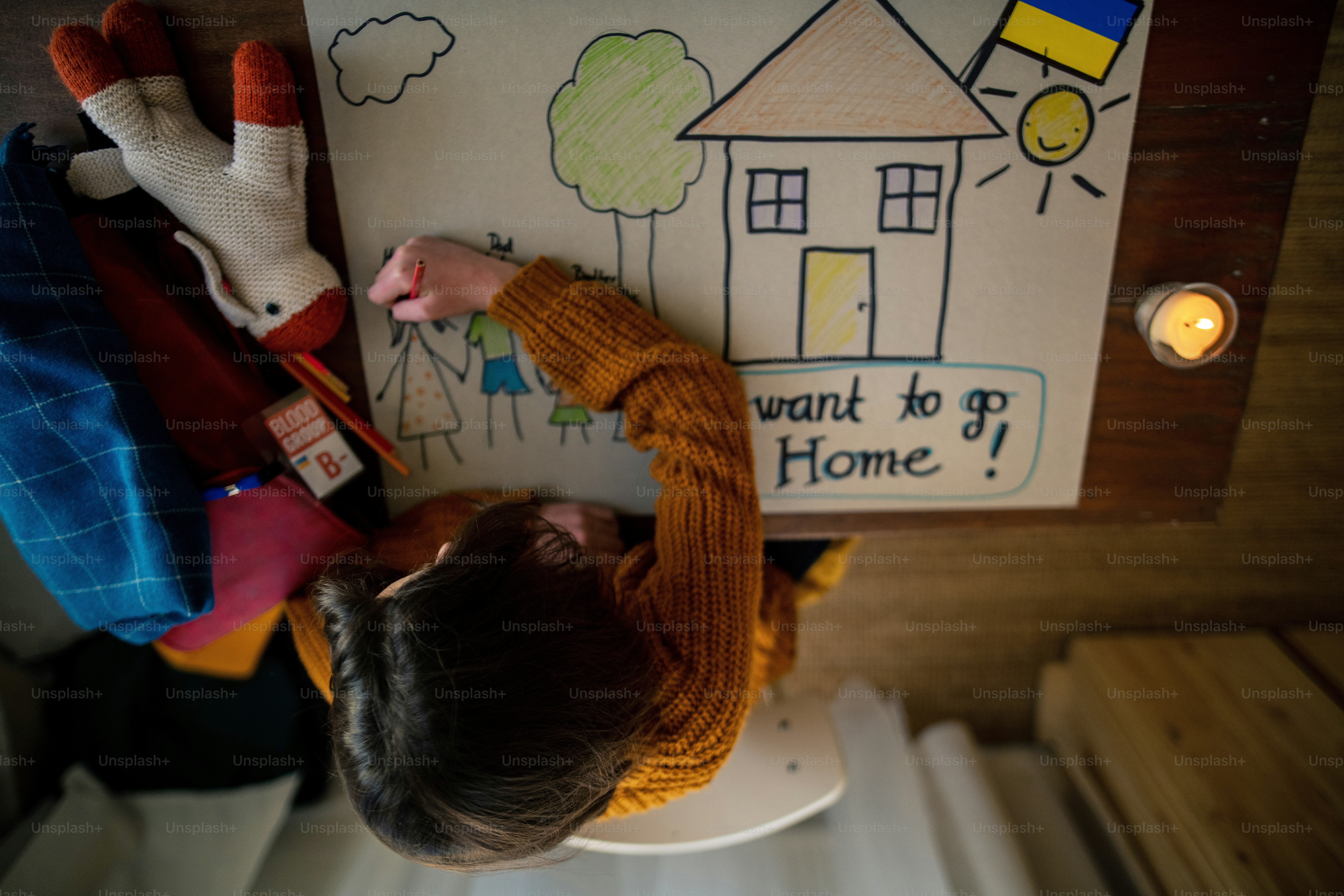 A top view of Ukrainian refugee schoolgirl missing home and drawing her ...