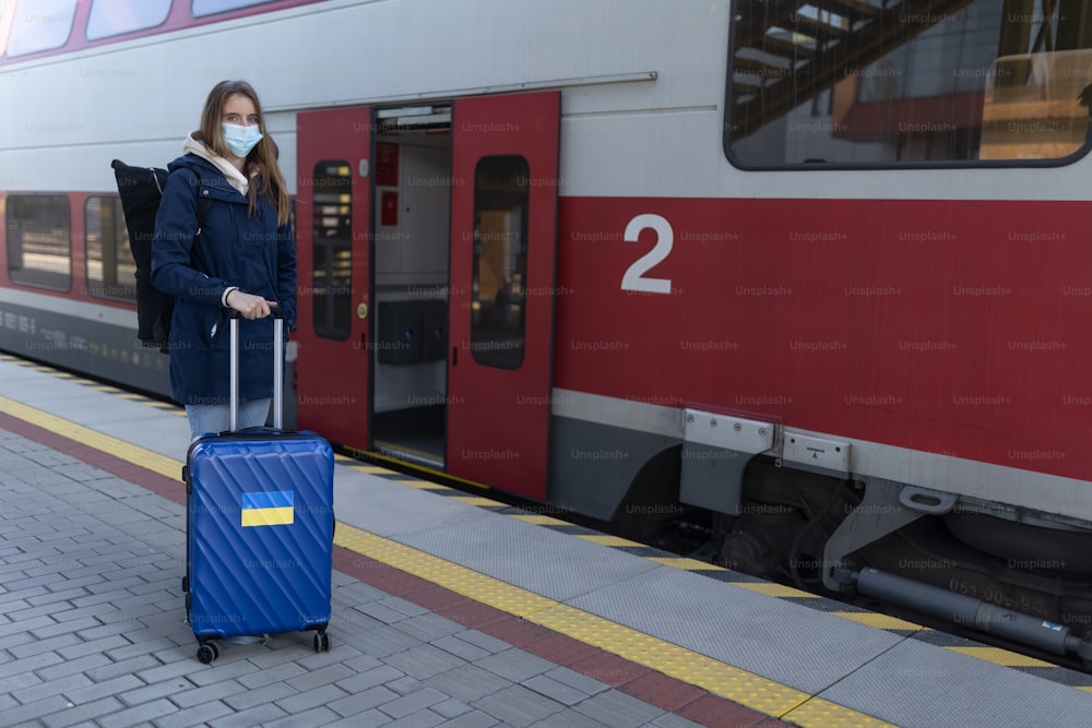 Une jeune femme ukrainienne avec une valise attendant le train à la ... Une jeune femme ukrainienne avec une valise attendant le train à la ...