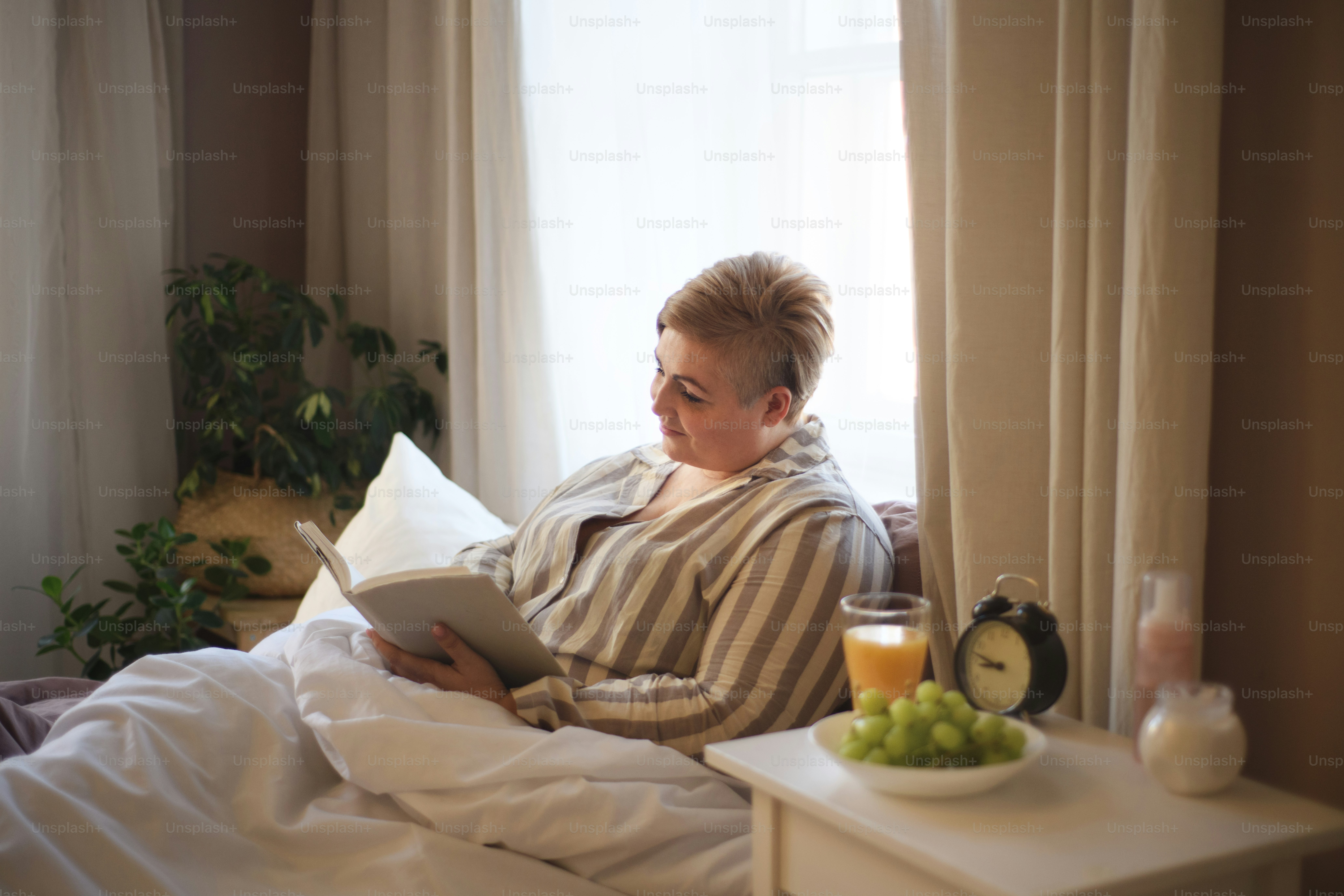 A happy overweight woman reading book in bed at home. photo – Plus size ...