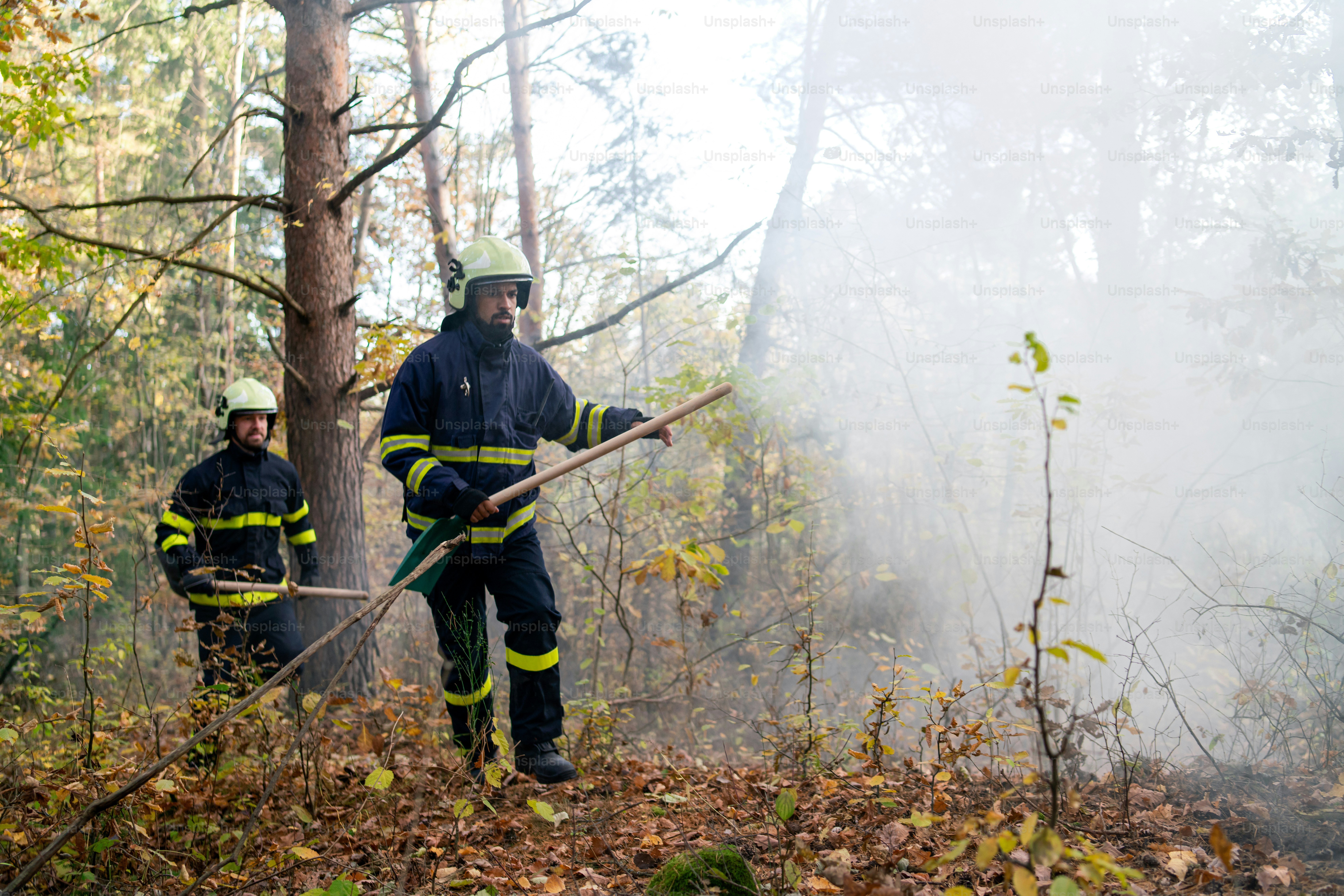 Firefighters men at action, running through the smoke with shovels to ...