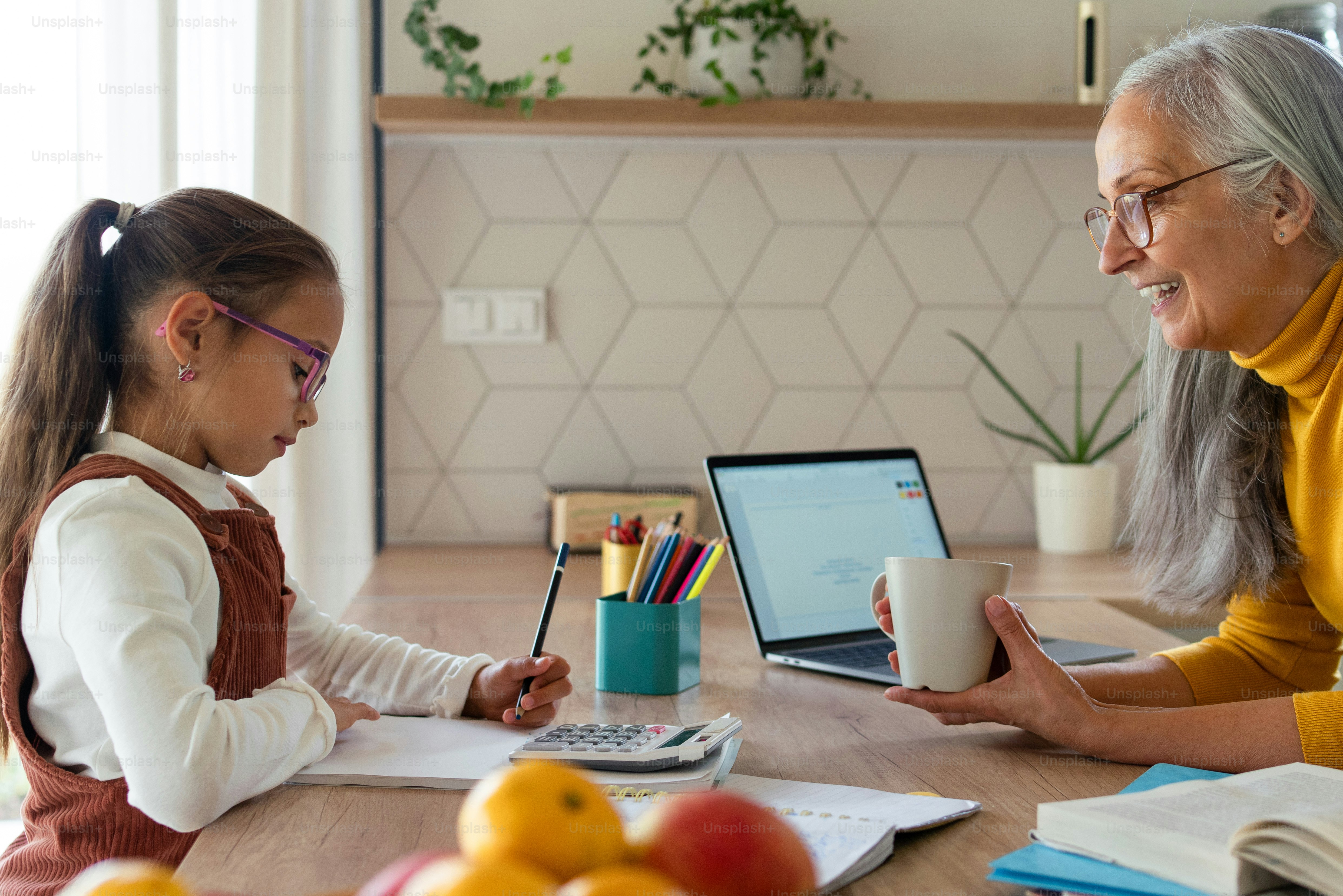 A small girl with senior grandmother doing homework at home. photo ...