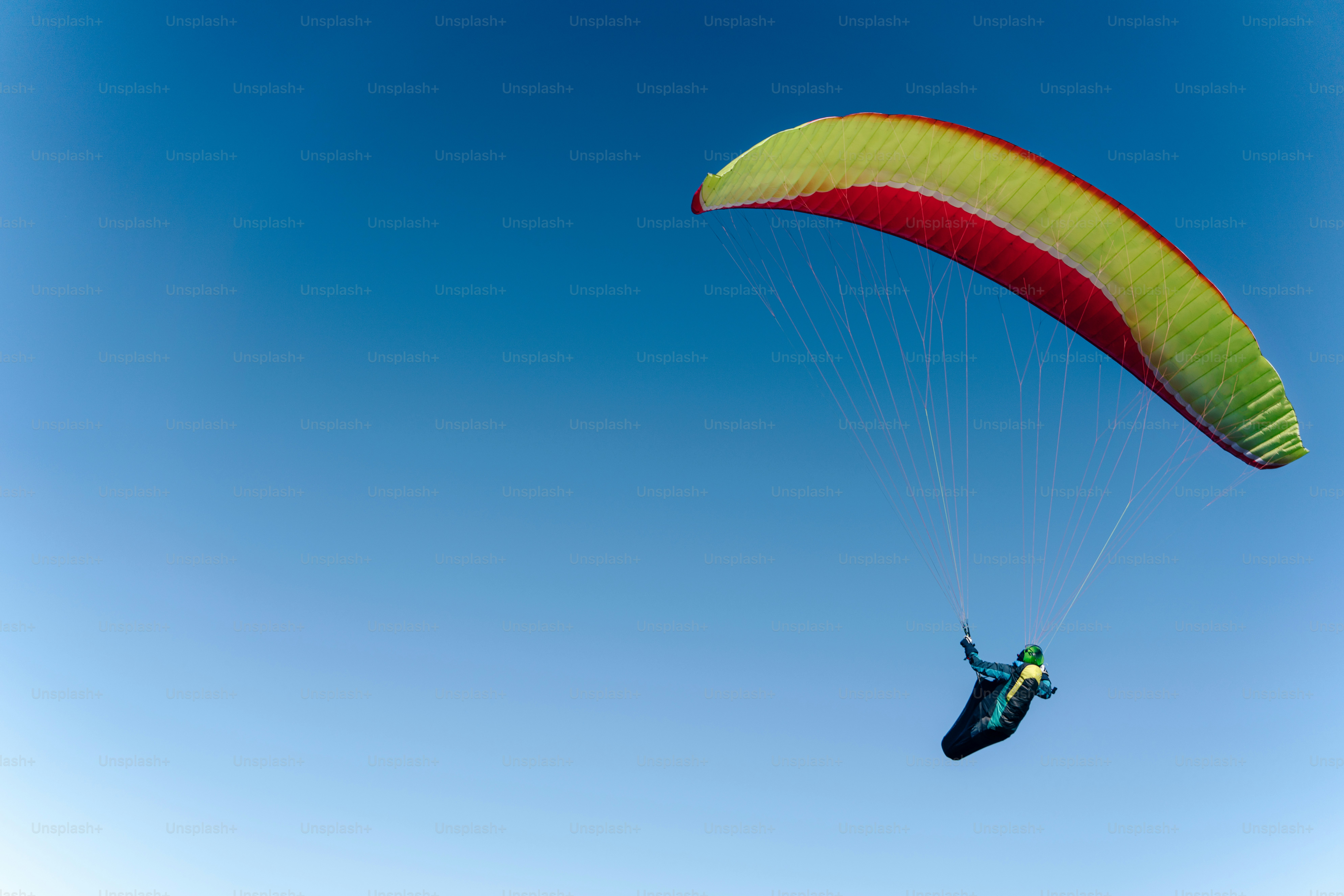 A paraglider in the blue sky. The sportsman flying on a paraglider ...