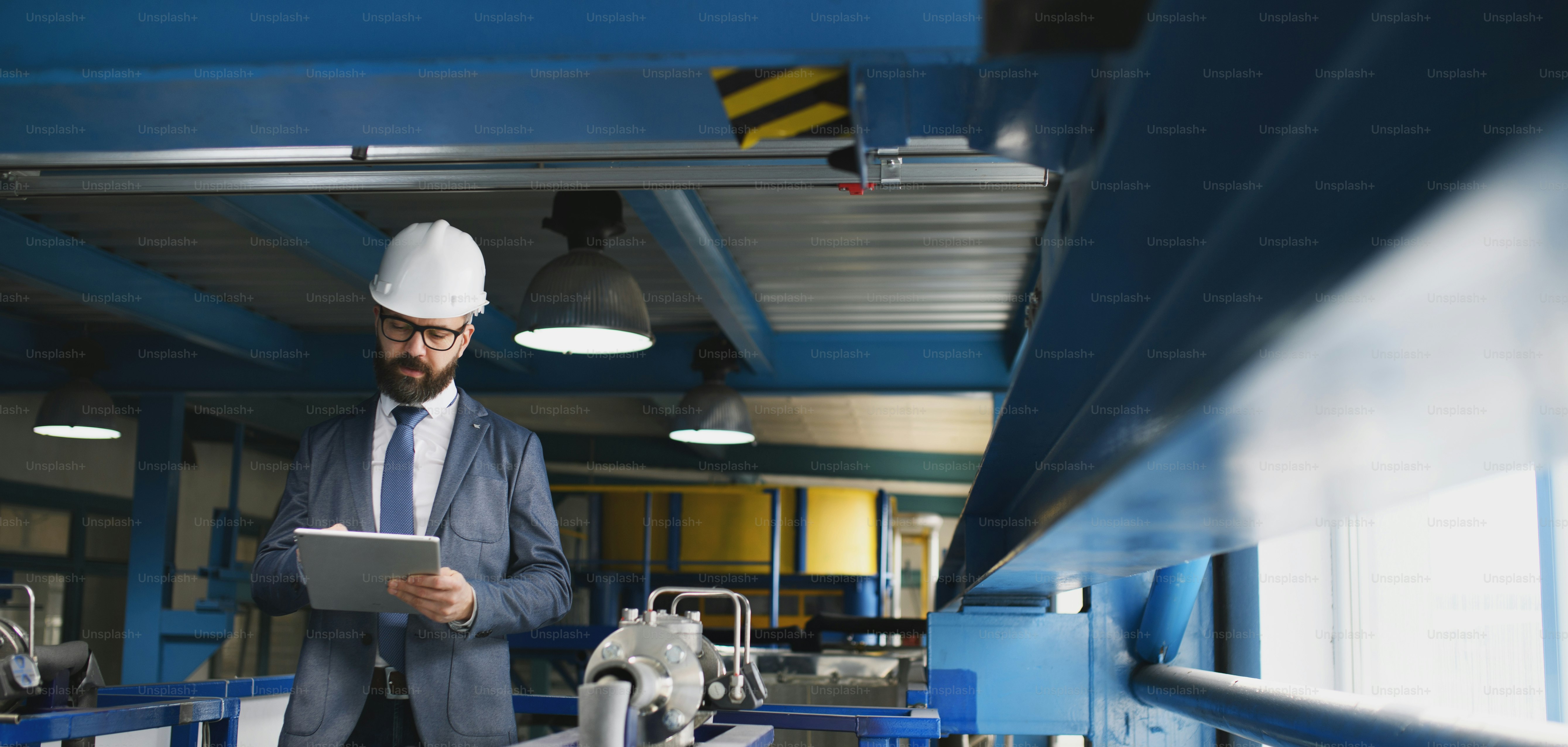 A chief Engineer in the hard hat walks through industrial factory while ...