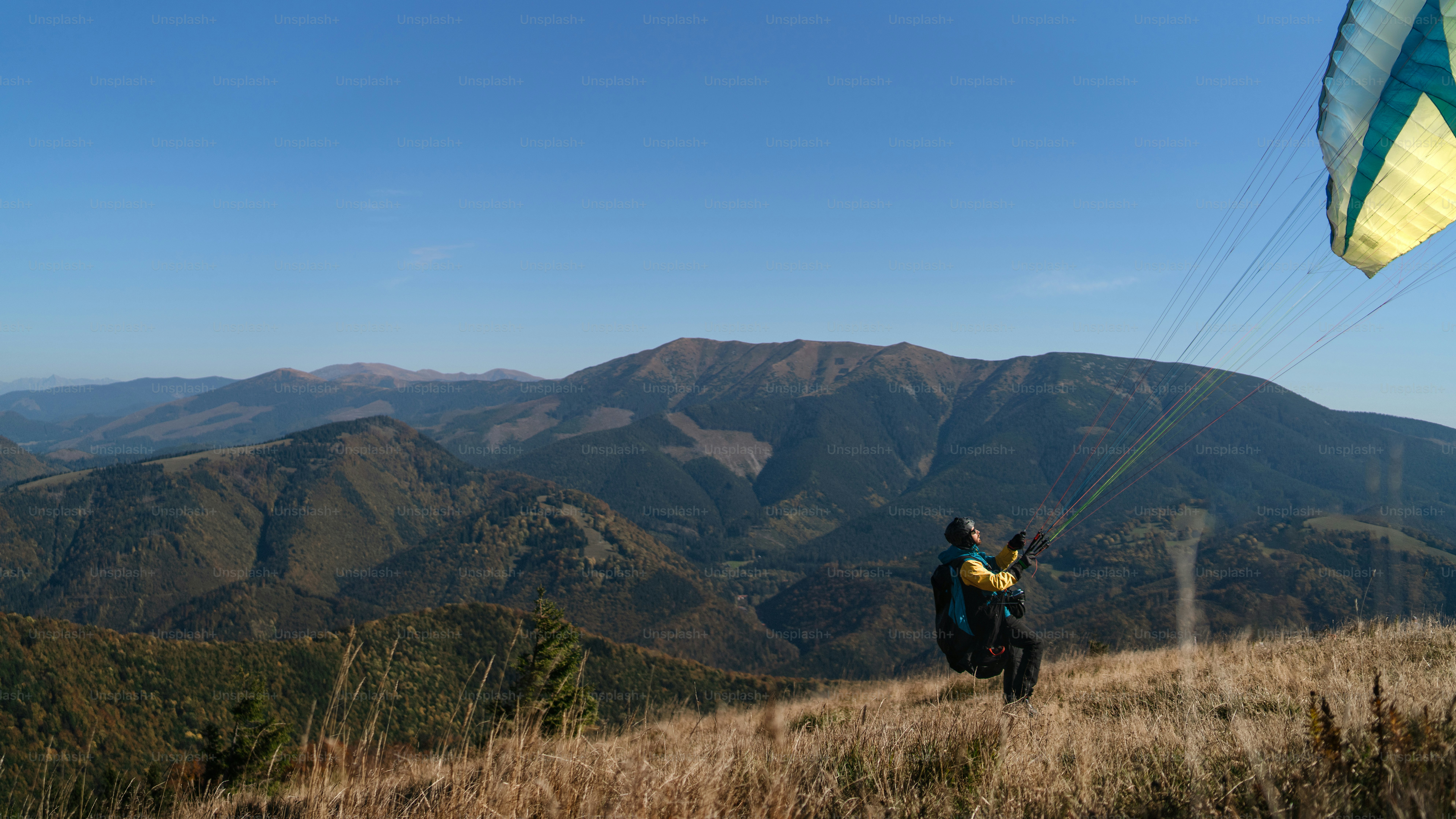 A paraglider landing on the ground against the blue sky. photo ...