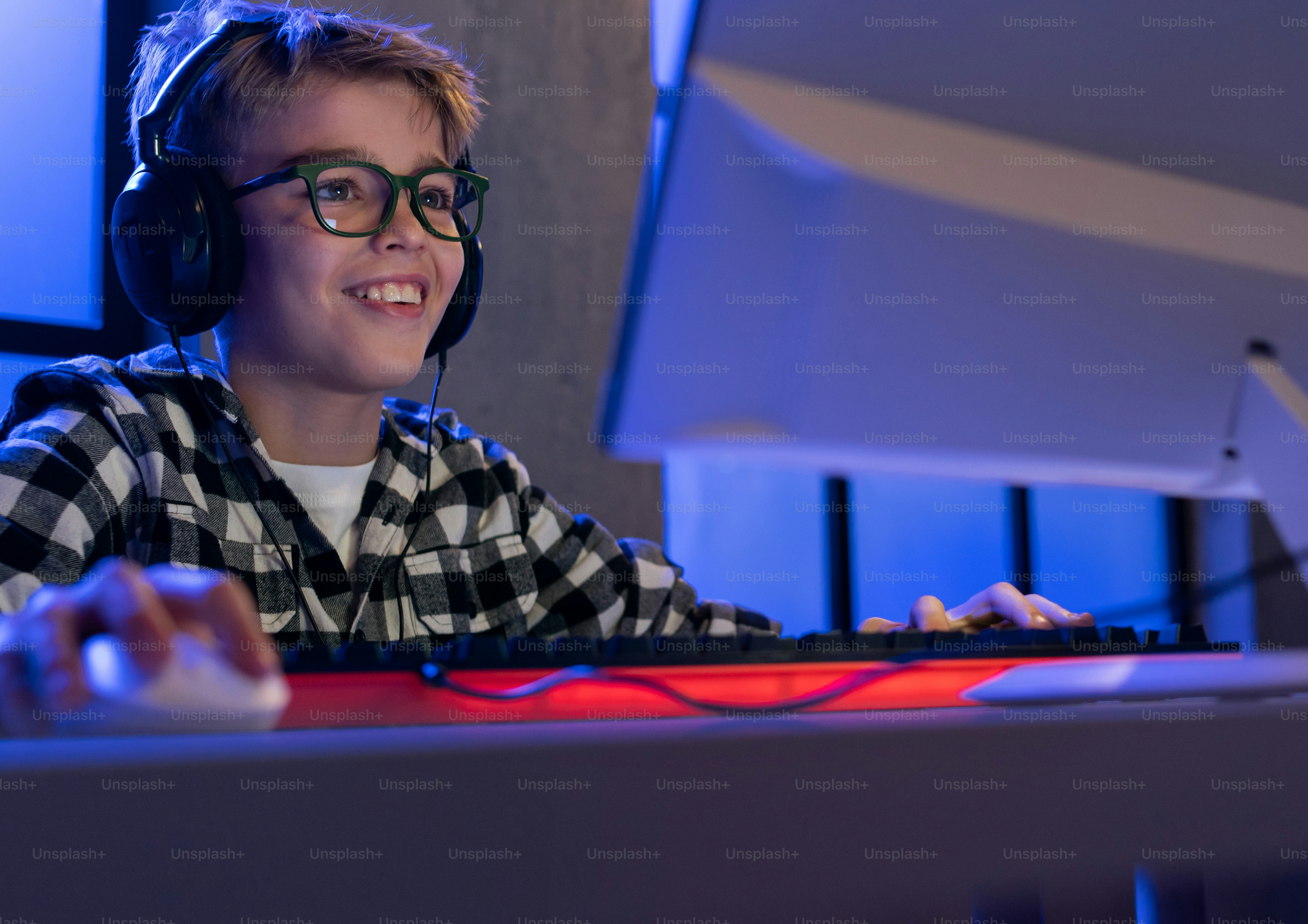 A young gamer boy with headphones playing computer video game. photo ...