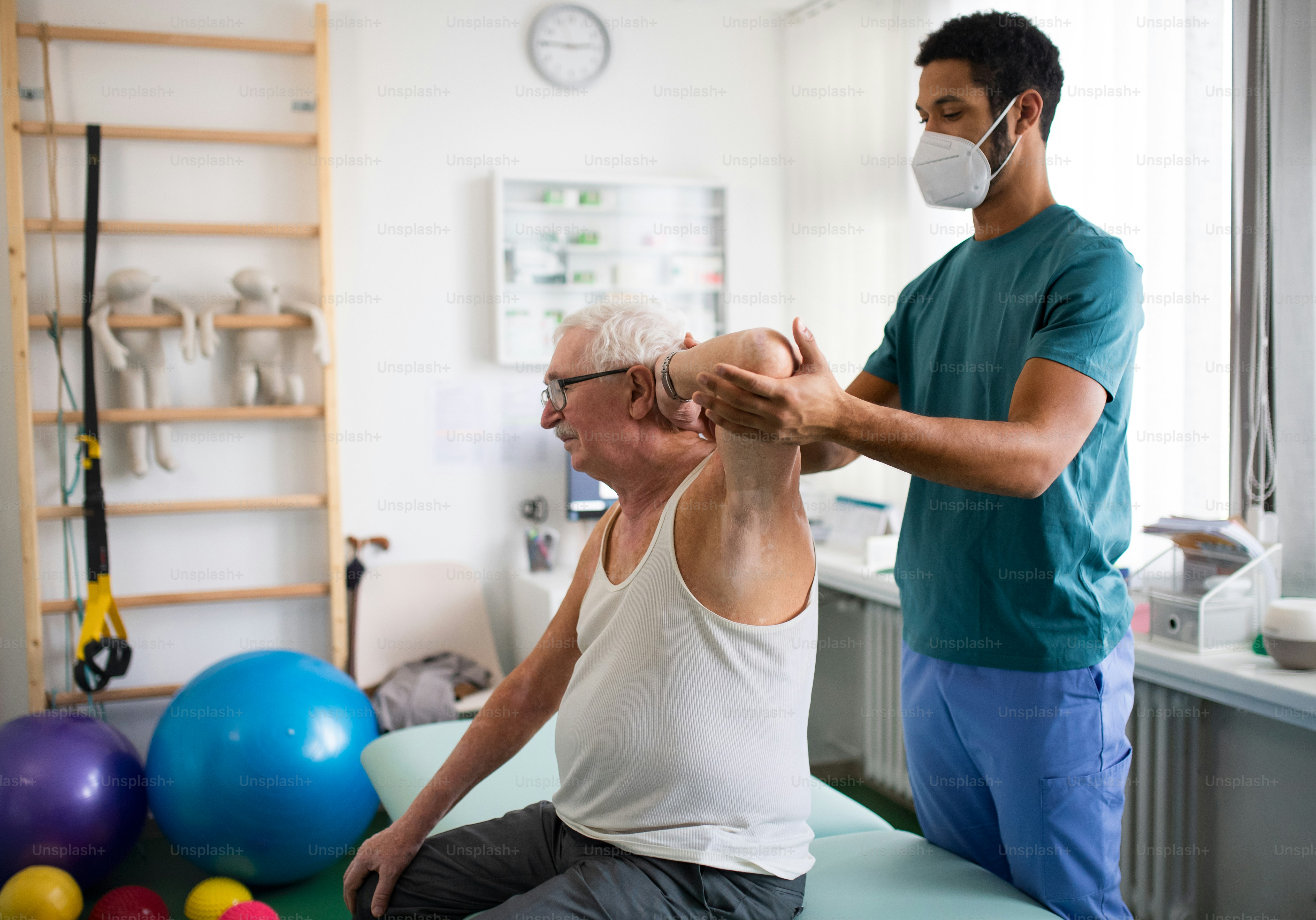 A young physiotherapist exercising with senior patient in a physic room ...
