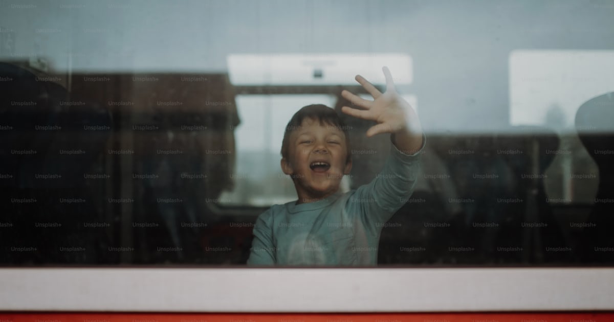 電車で移動中、窓から手を振ってさよならを言う幸せな少年。の写真 スロバキア Unsplashの写真