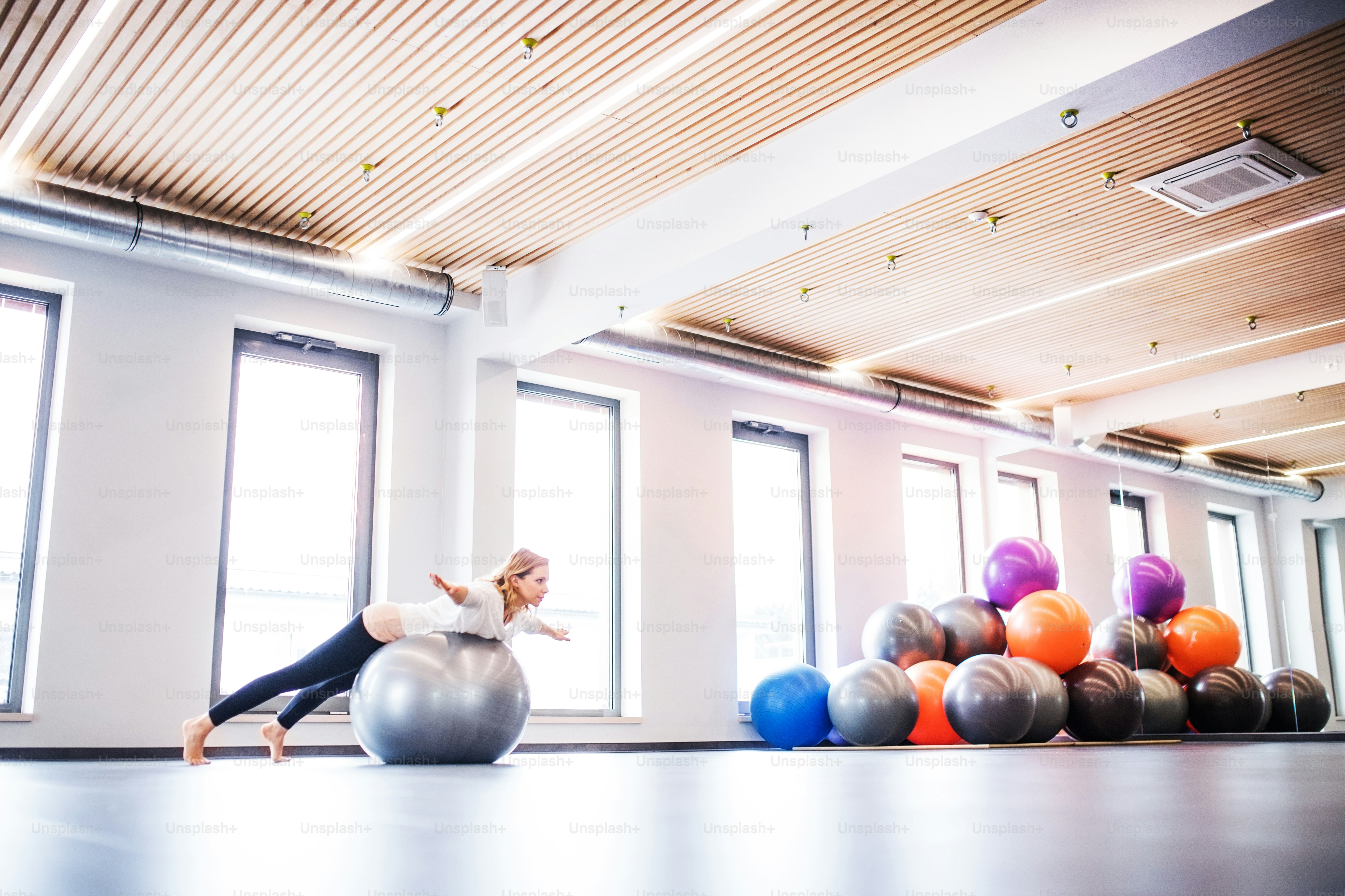 Young beautiful woman doing exercise with a fitball in a gym. photo ...