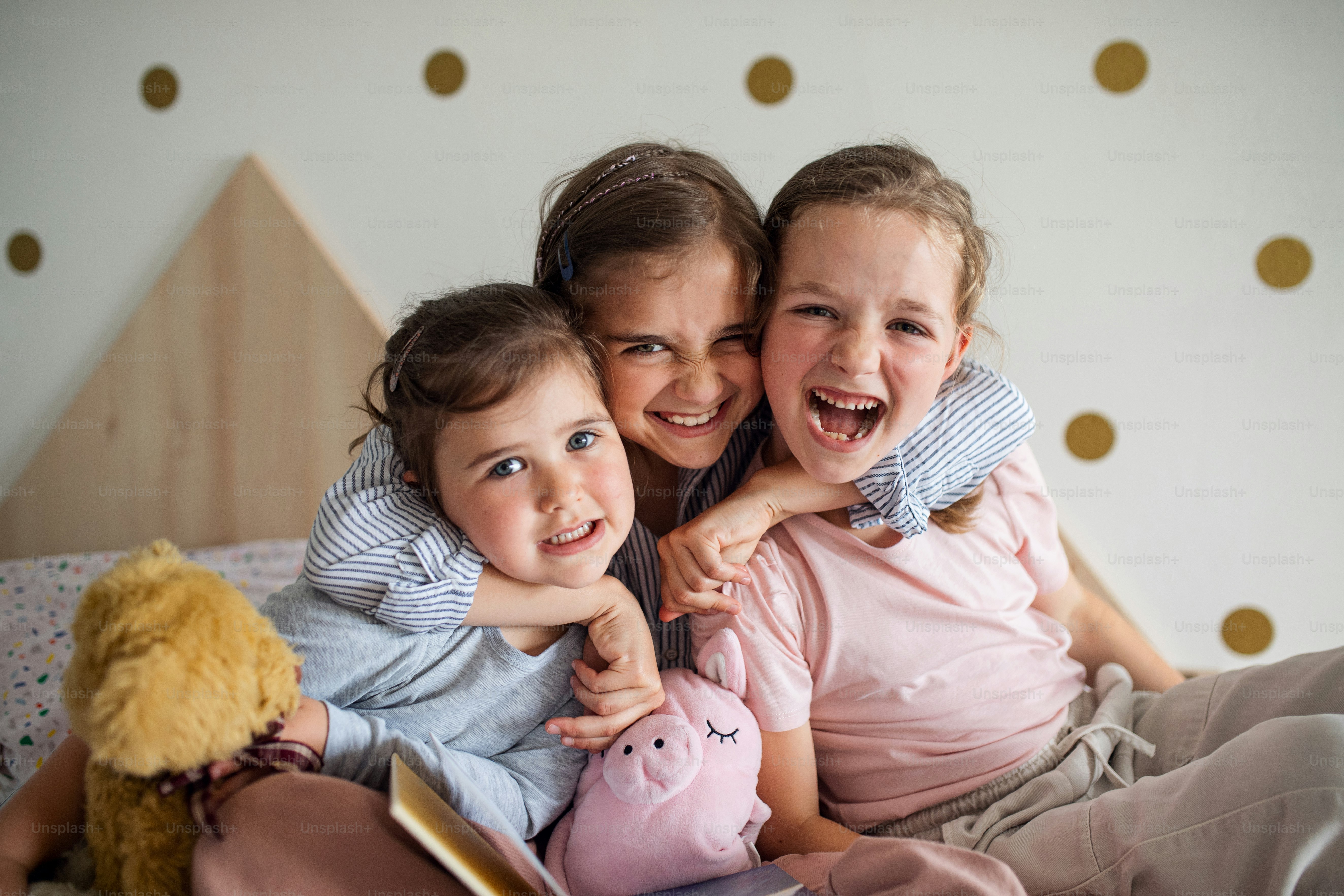 A portrait of three girls sisters indoors at home, playing. photo ...