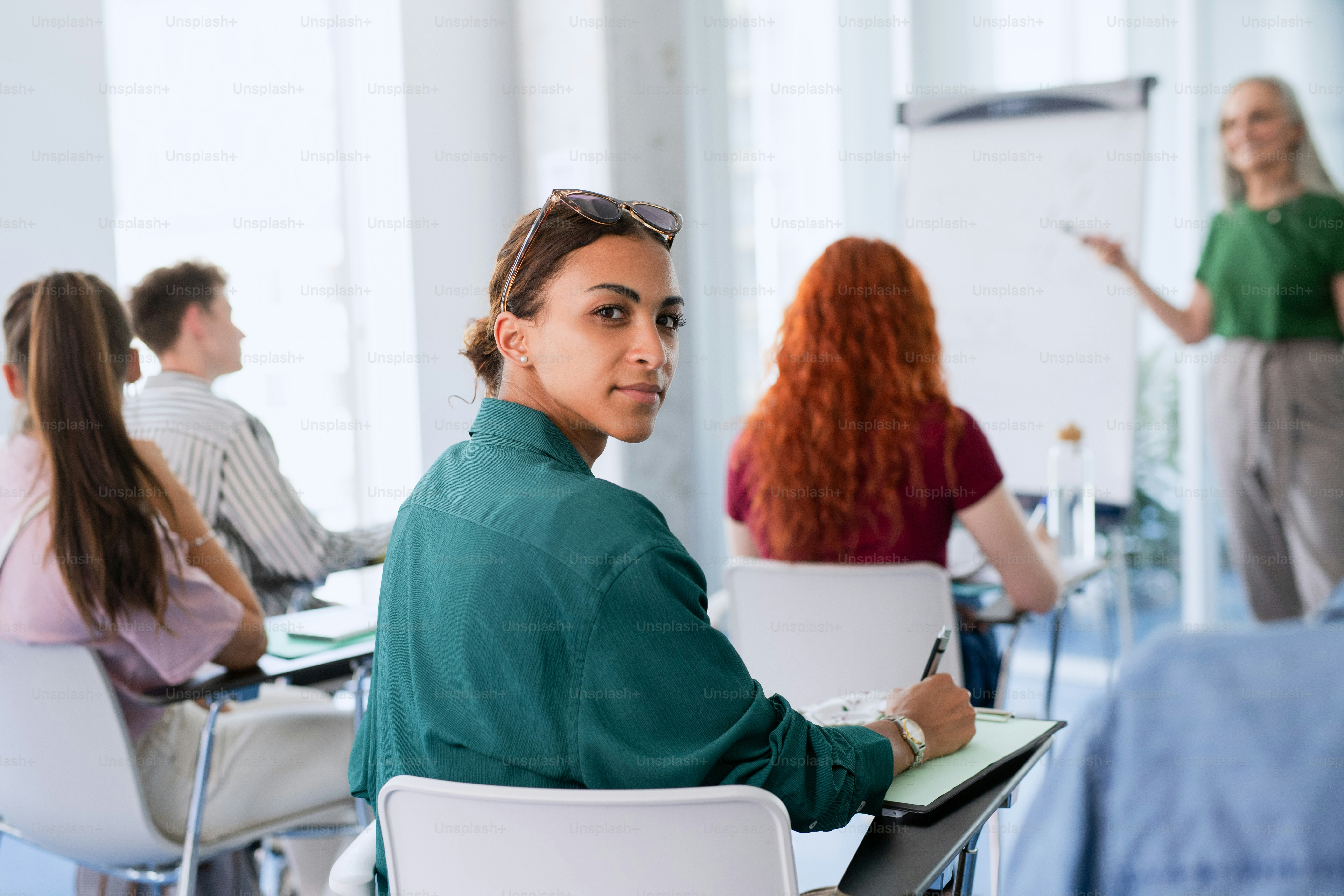 A portrait of young university student sitting in classroom indoors ...