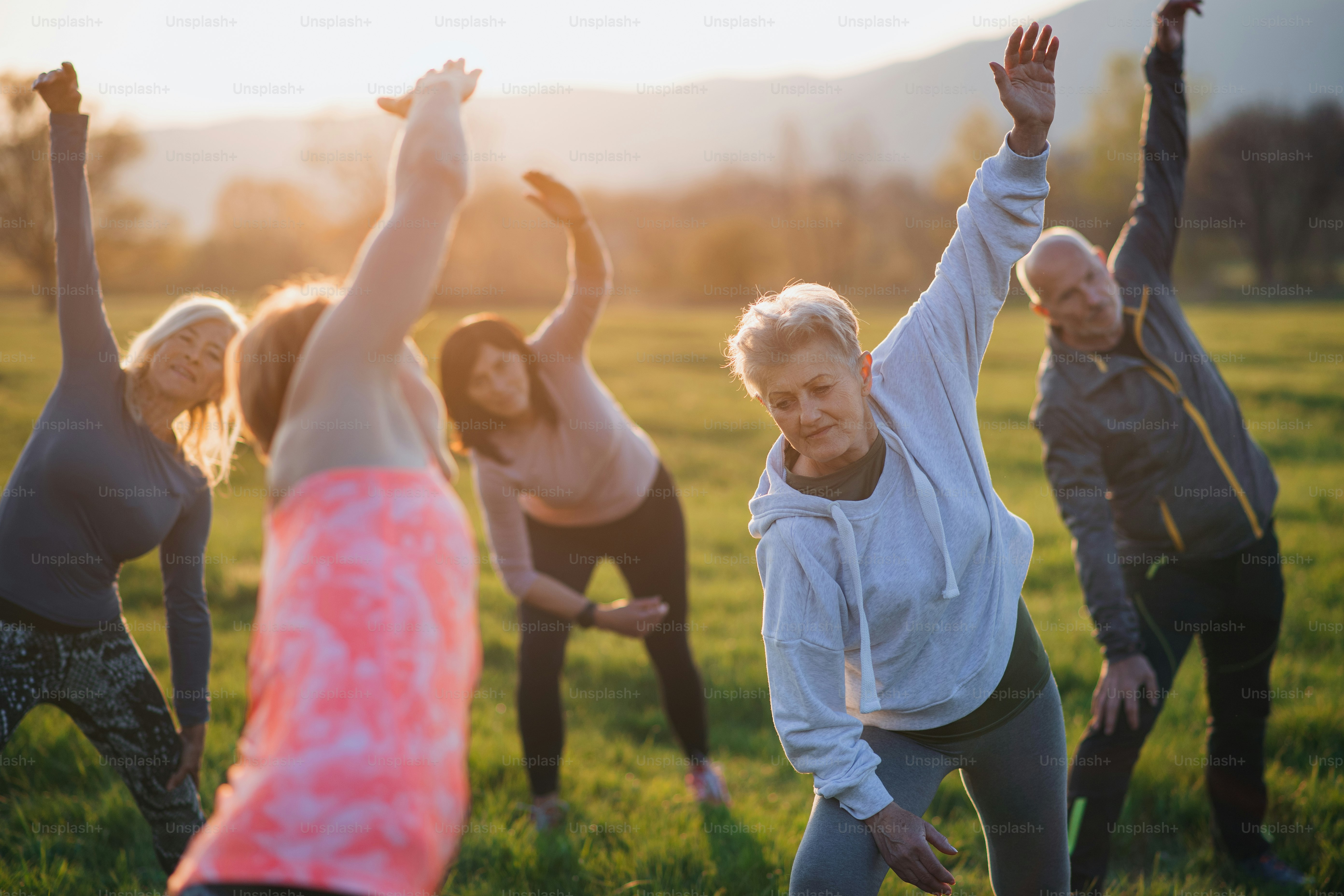 A group of seniors with sport instructor doing exercise outdoors in ...