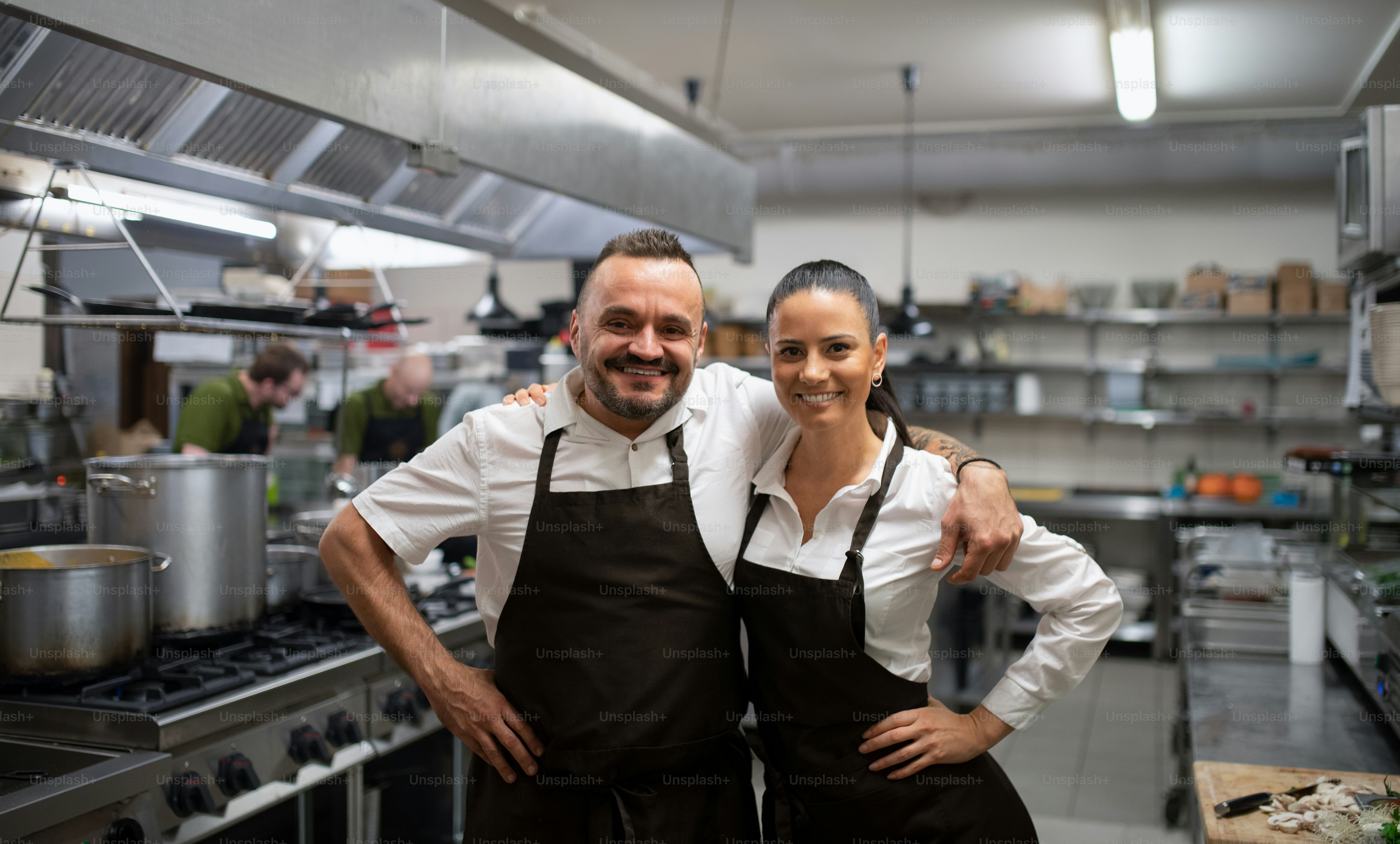 Confident chefs colleagues standing with arms around and looking at a ...