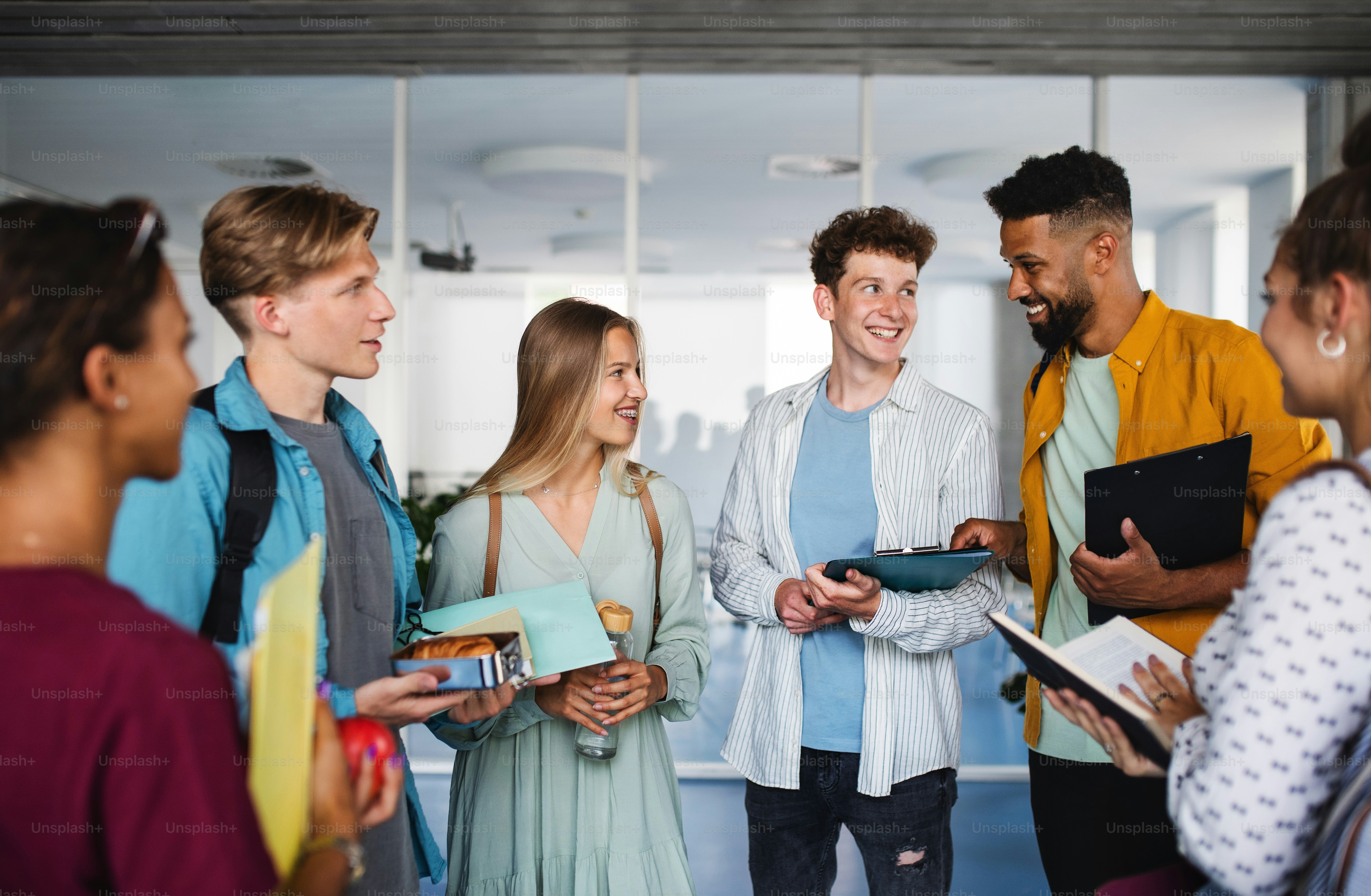 Group of cheerful university students standing in corridor indoors ...