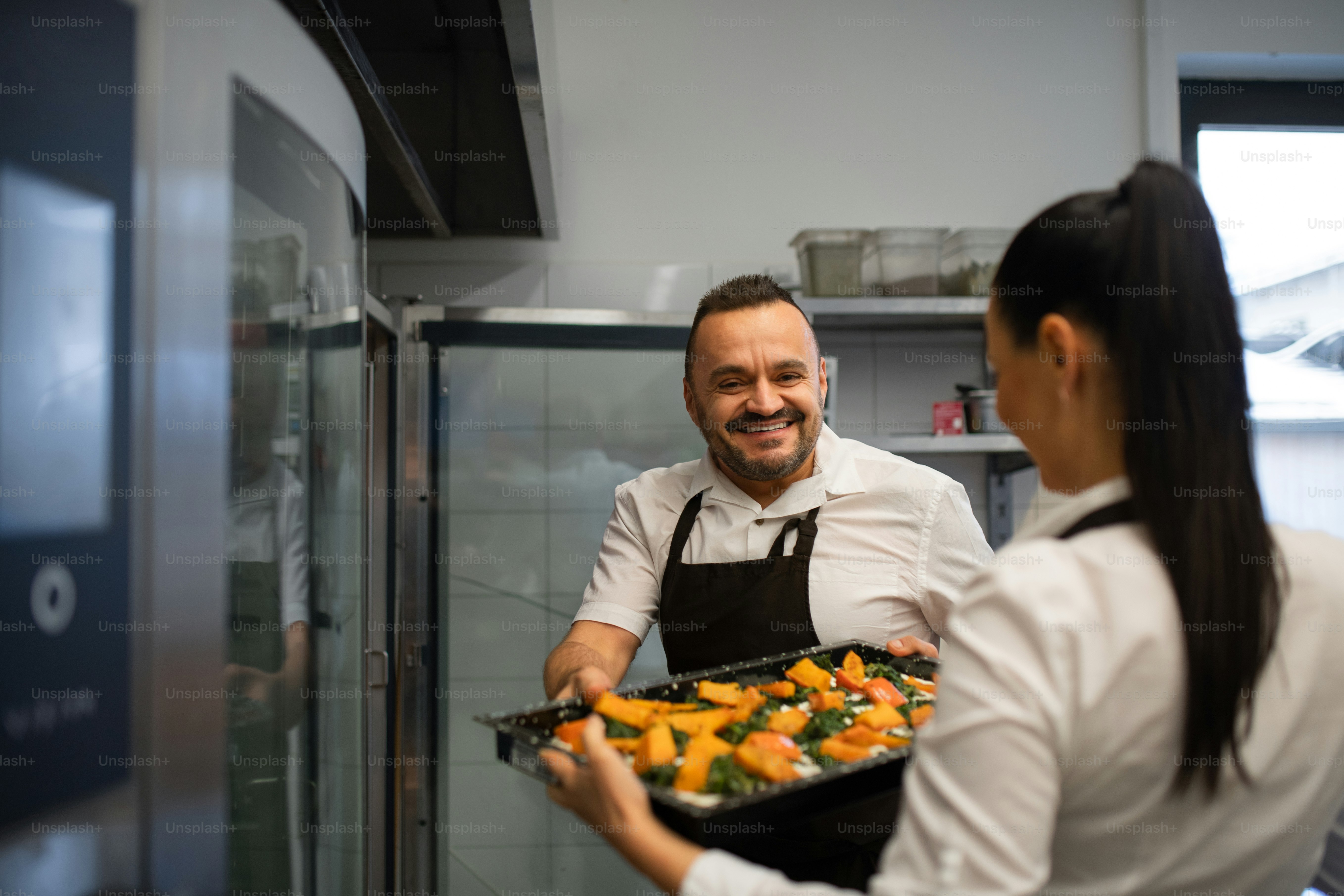 A chef and cook working on their dishes indoors in restaurant kitchen ...