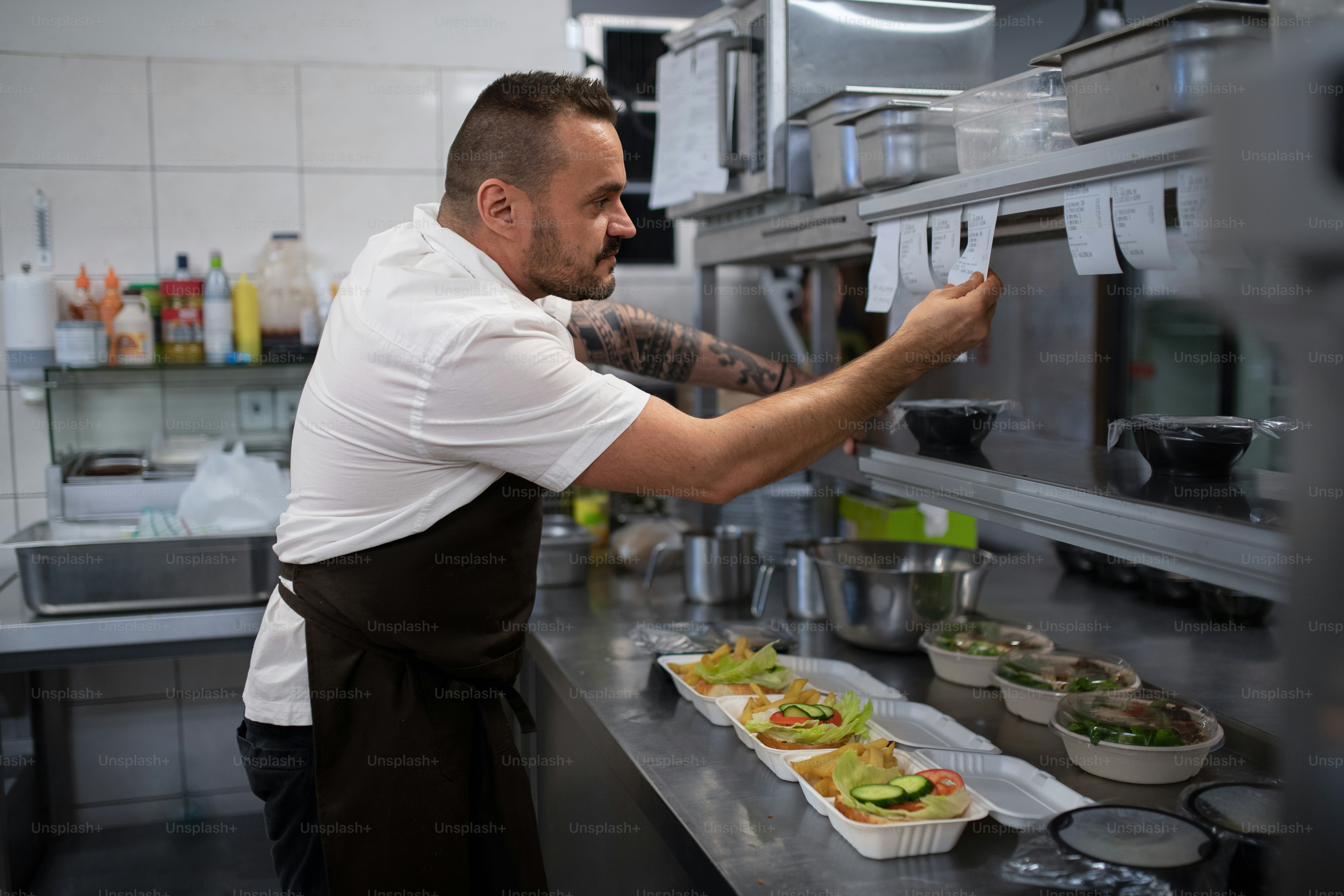 A chef taking order slip in commercial kitchen. photo – Responsible ...