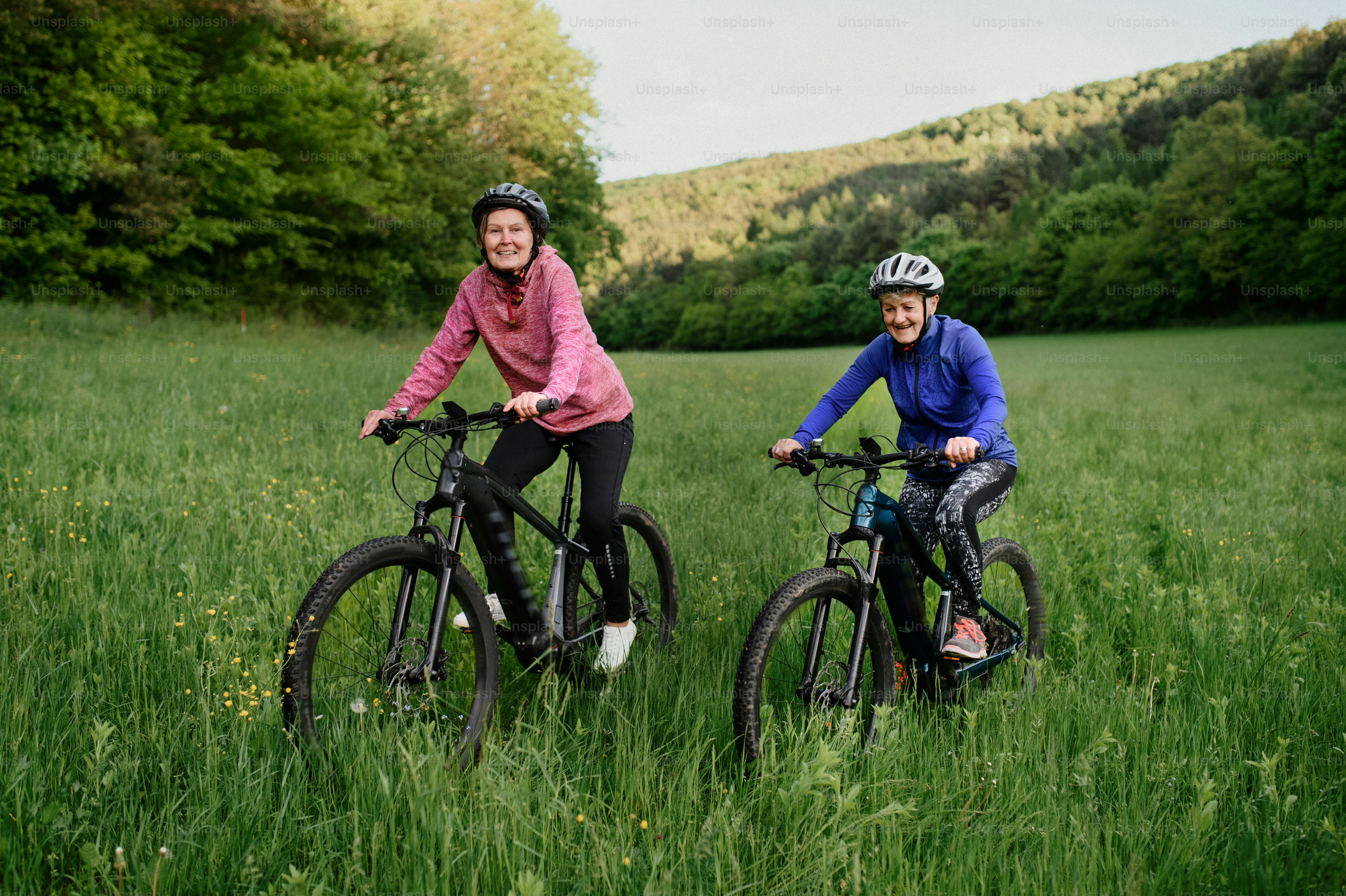 Happy active senior women friends cycling together outdoors in the ...