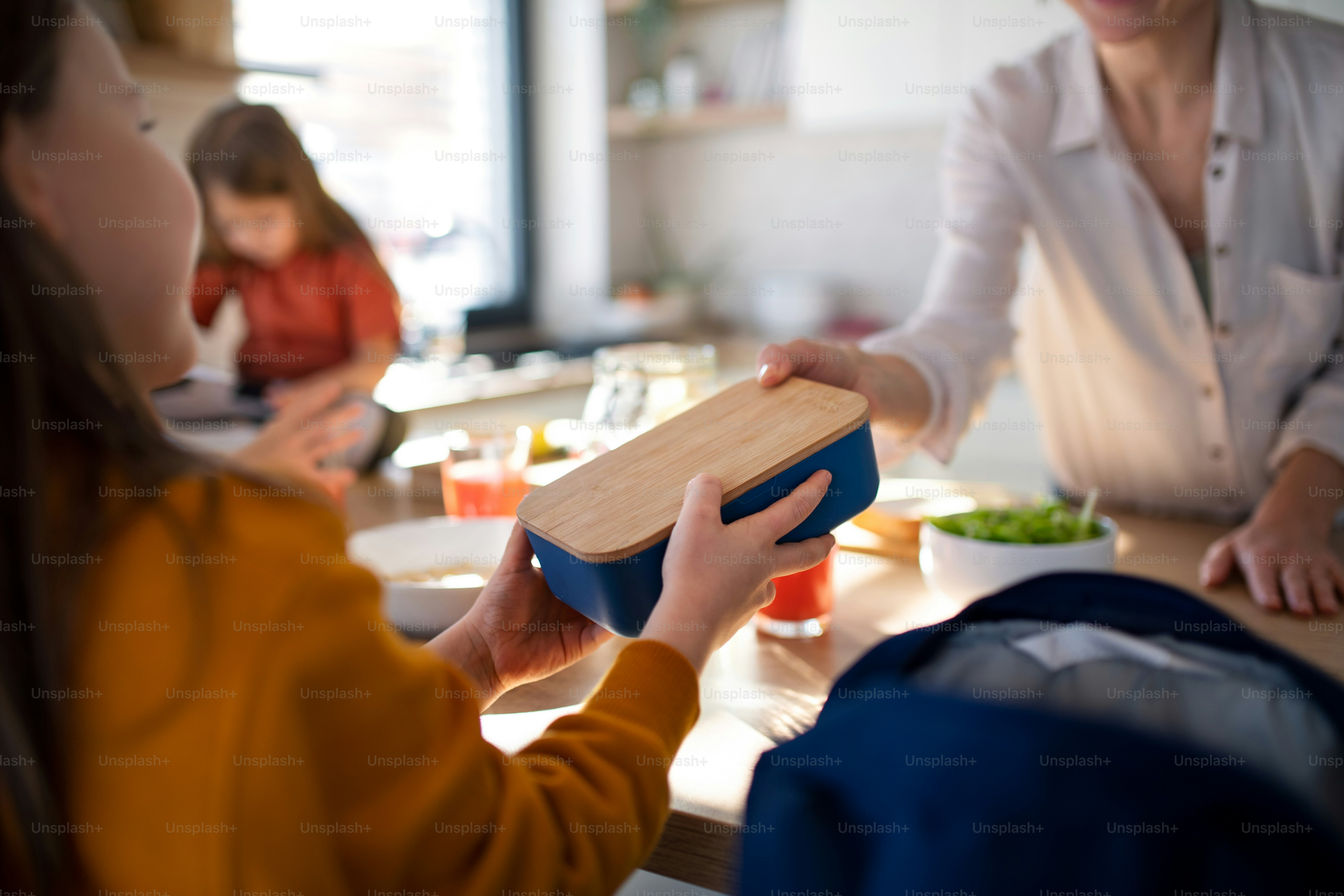 Little children packing lunch boxes to school in morning in the kitchen ...