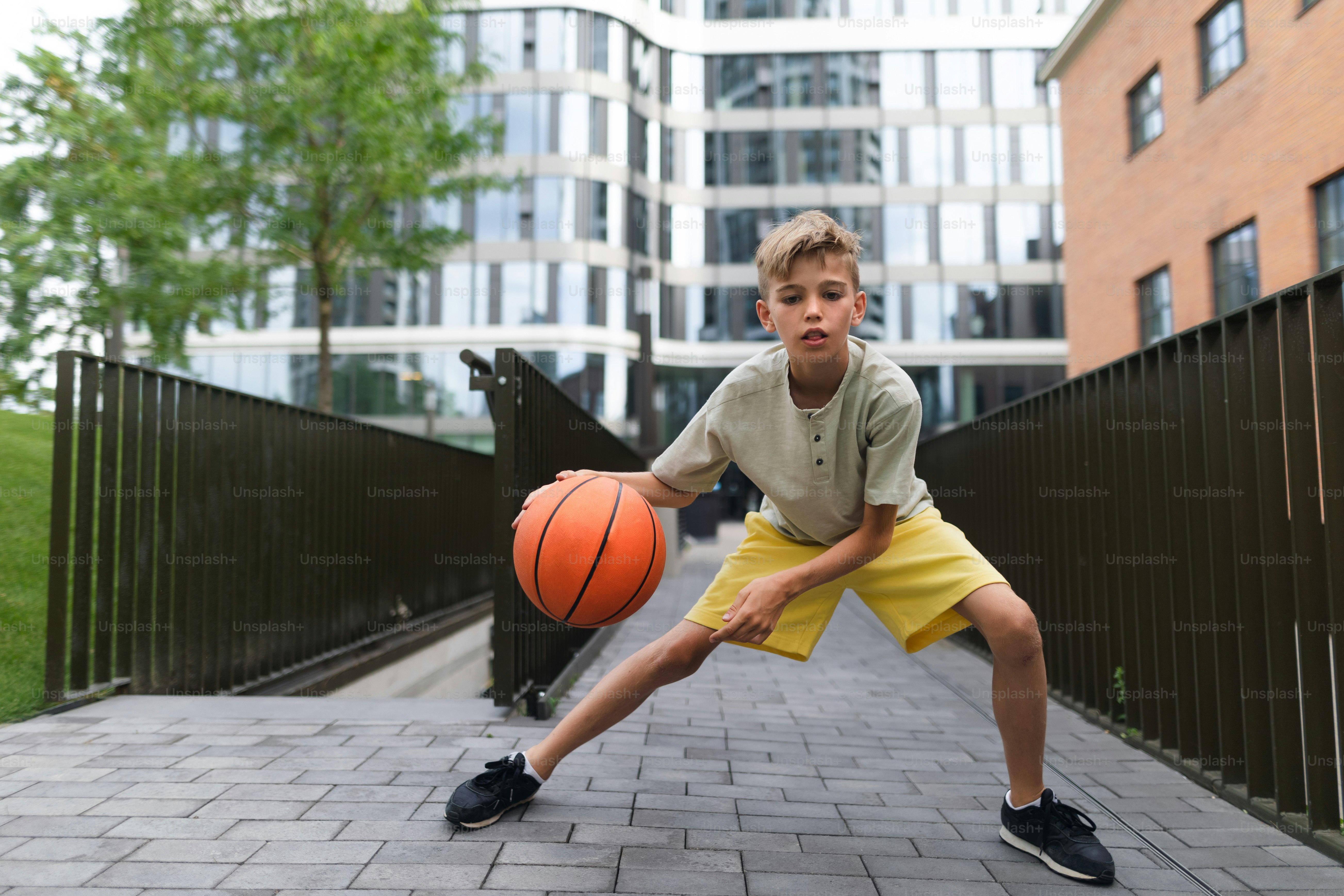 Foto Muchacho caucásico alegre regateando con pelota de baloncesto en ...