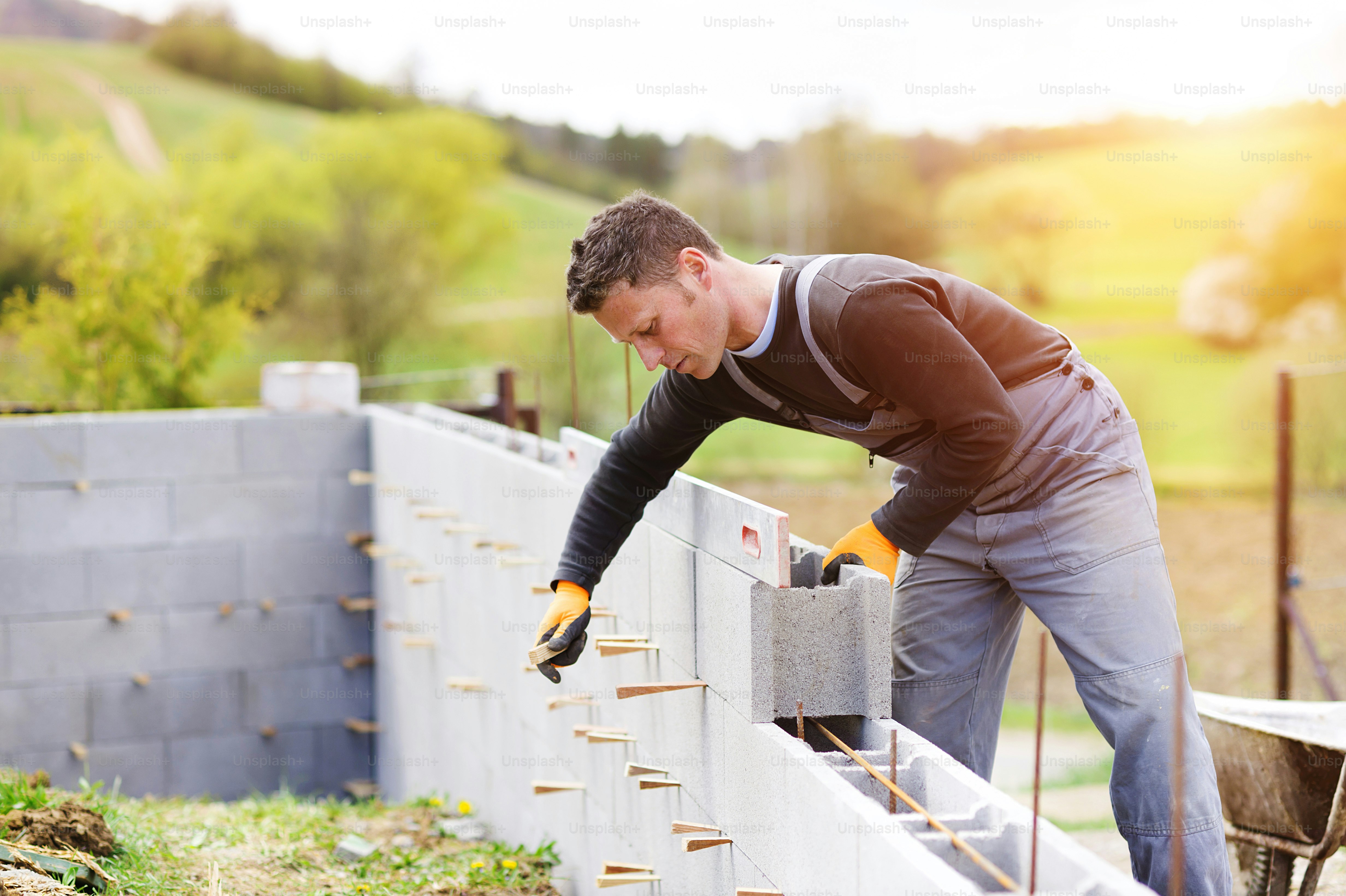 Bricklayer putting down another row of bricks in site photo ...