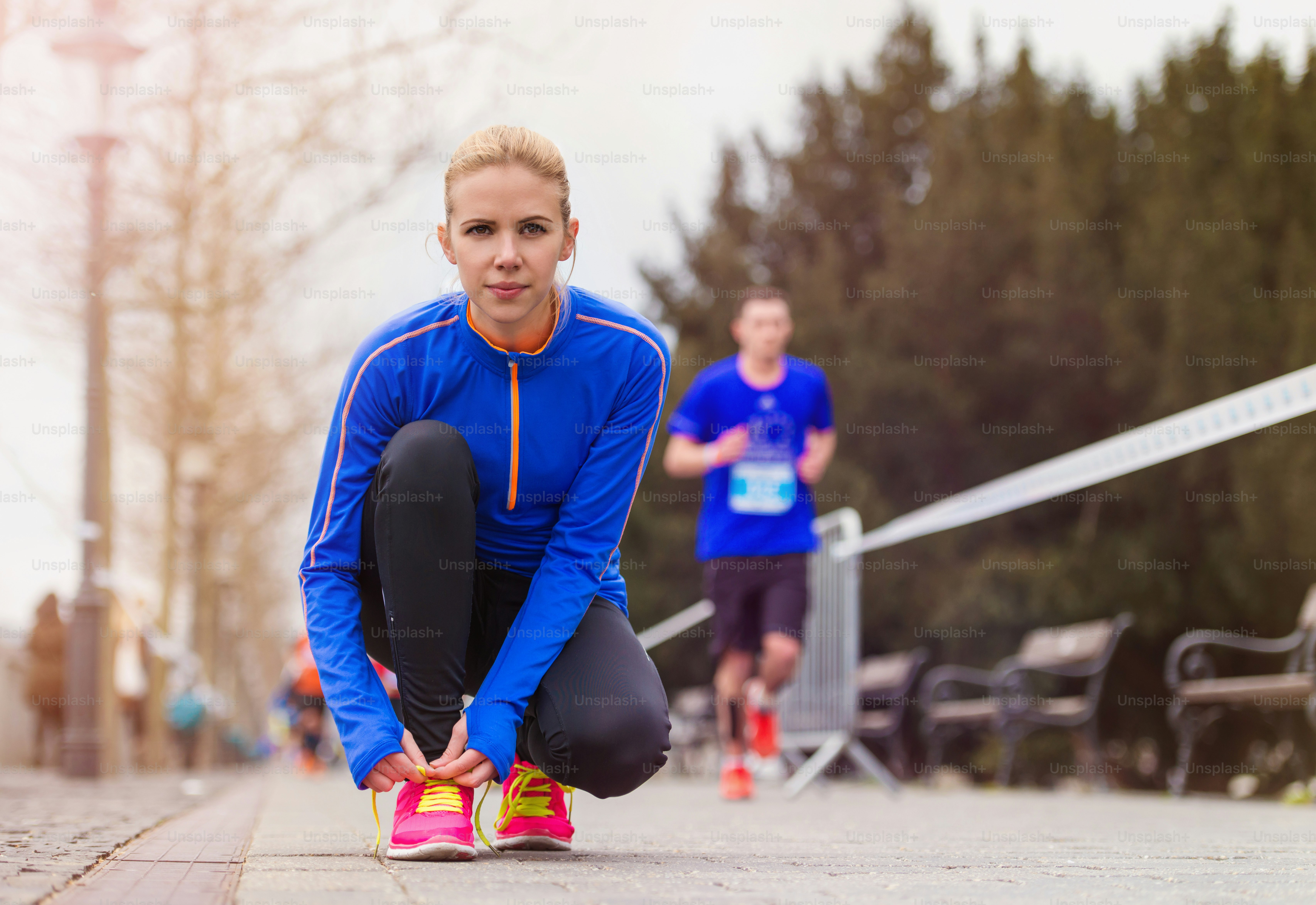 Young runner in the city race tying shoelaces photo – Exercising Image ...
