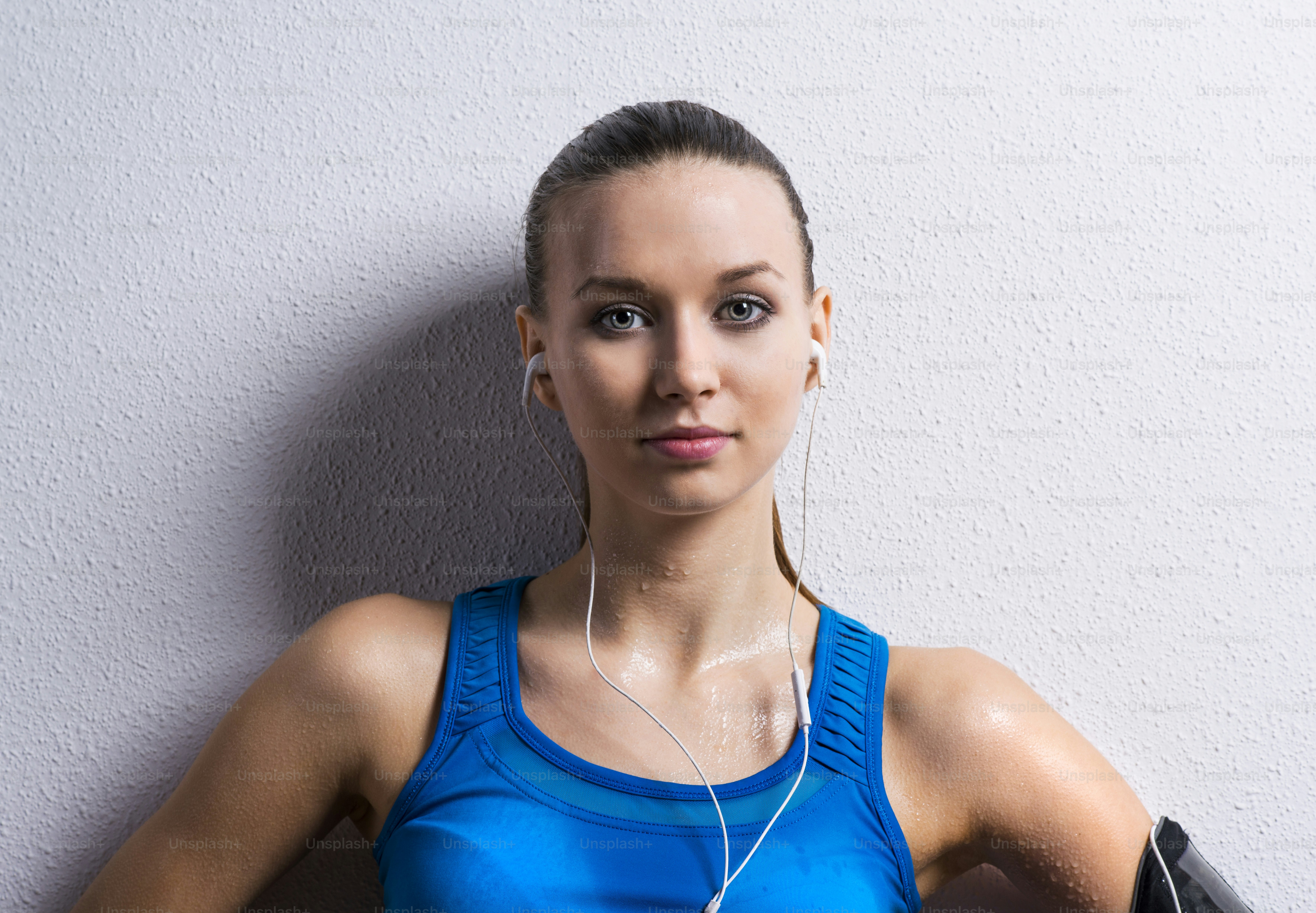 Beautiful young runner in a blue singlet. Studio shot on a white ...