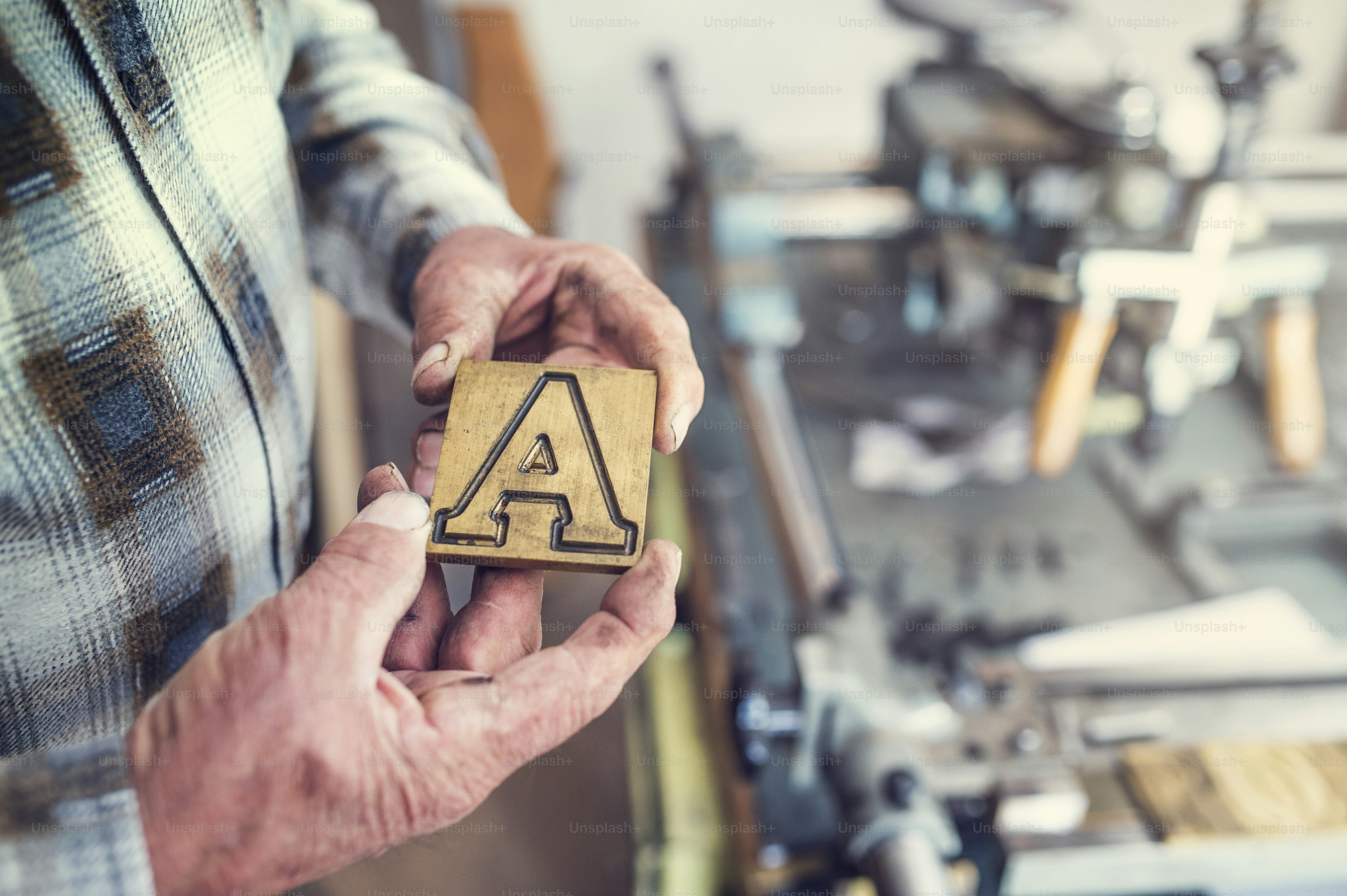 Senior man holding a letter that is used for engraving photo – Alphabet ...
