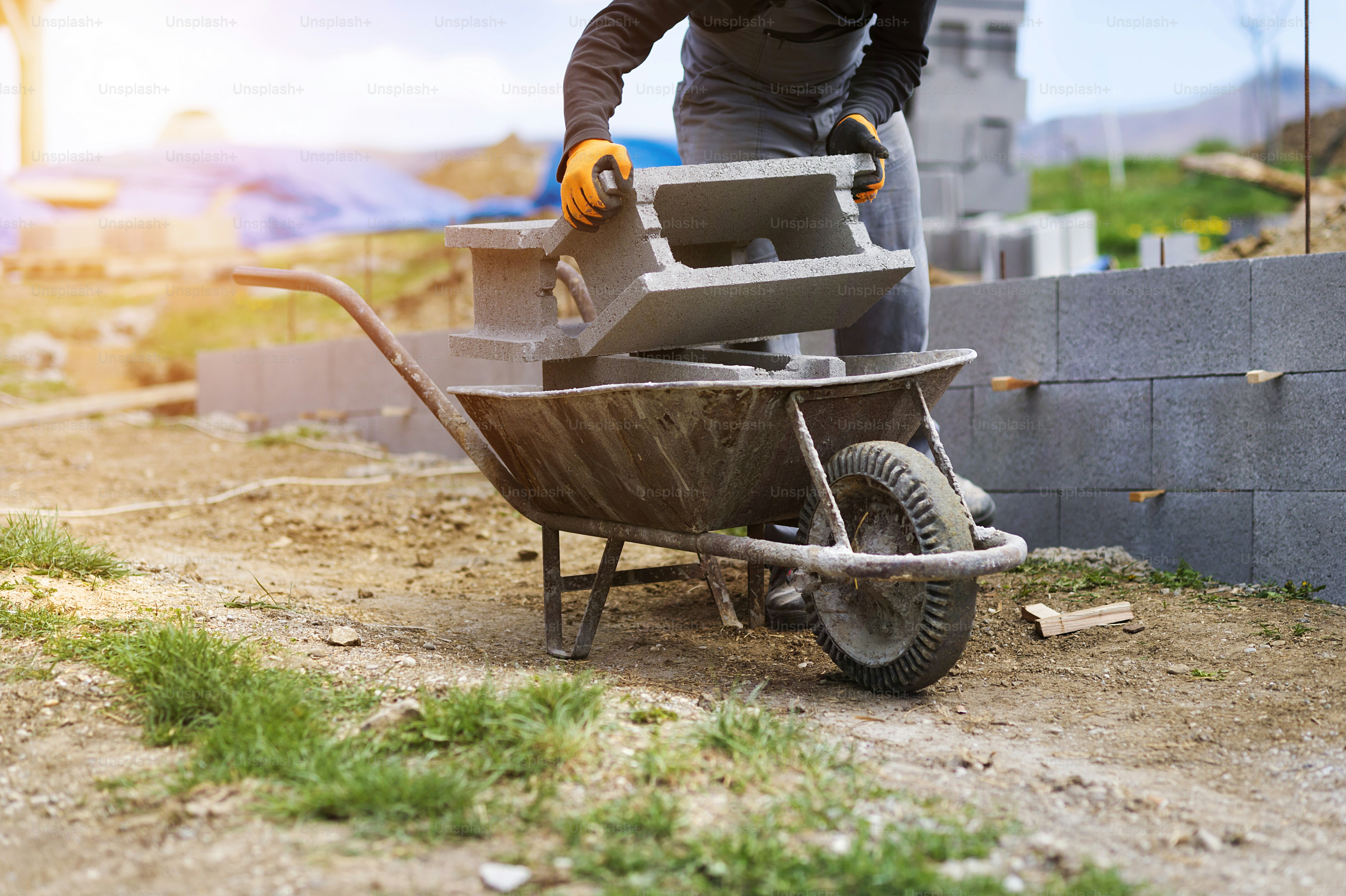 Bricklayer taking another brick from a wheelbarrow photo – Concrete ...