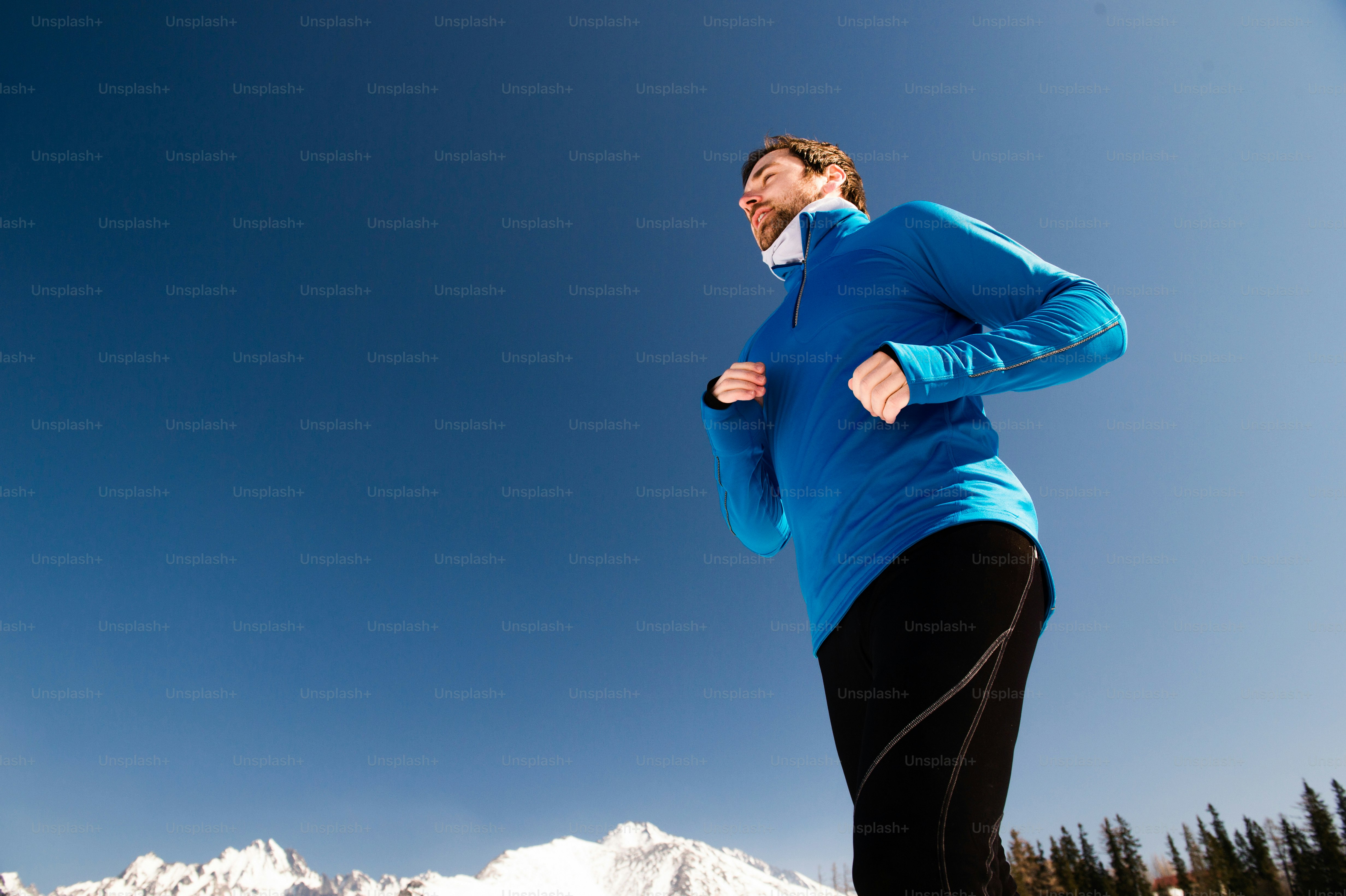 Young man jogging outside in sunny winter mountains photo – Exercising ...