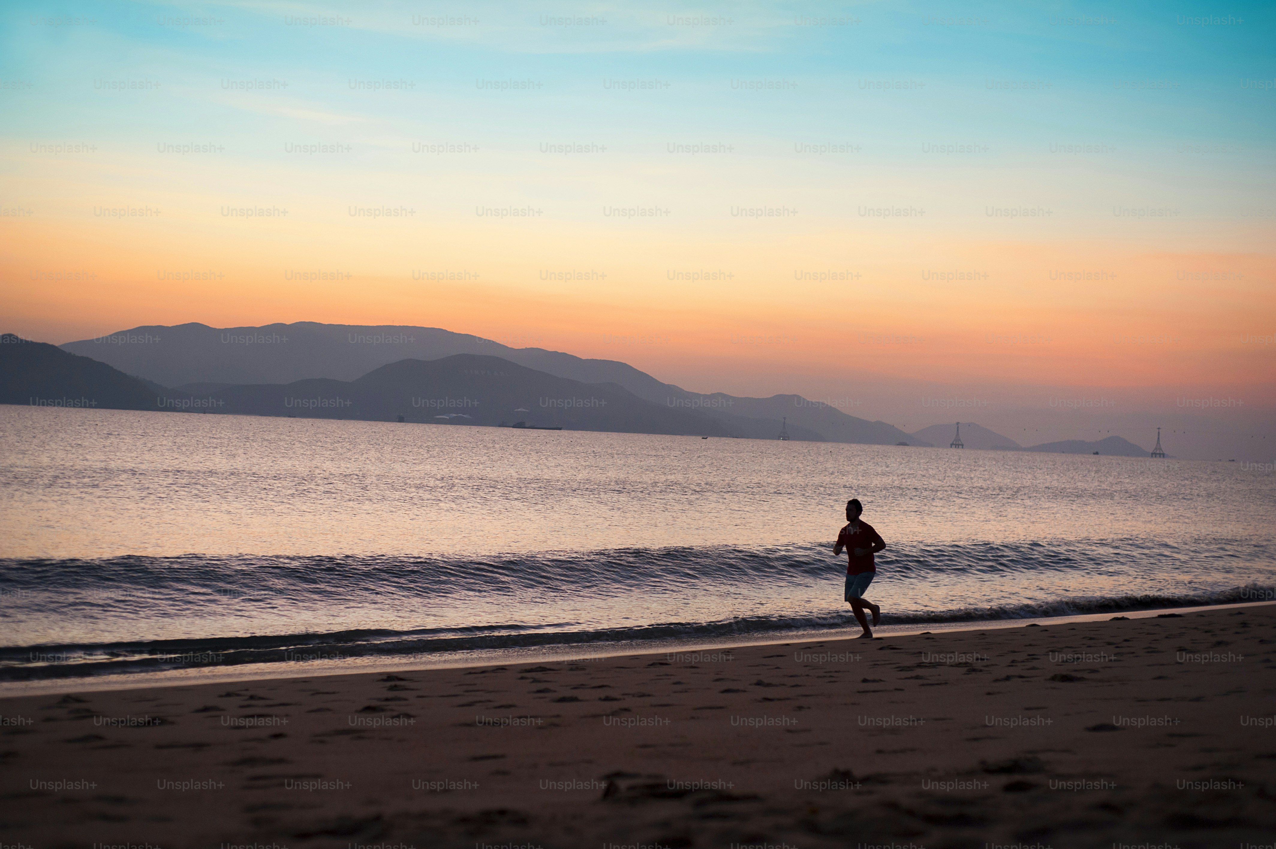 Young man running on the beach at sunset photo – Beautiful ocean Image ...